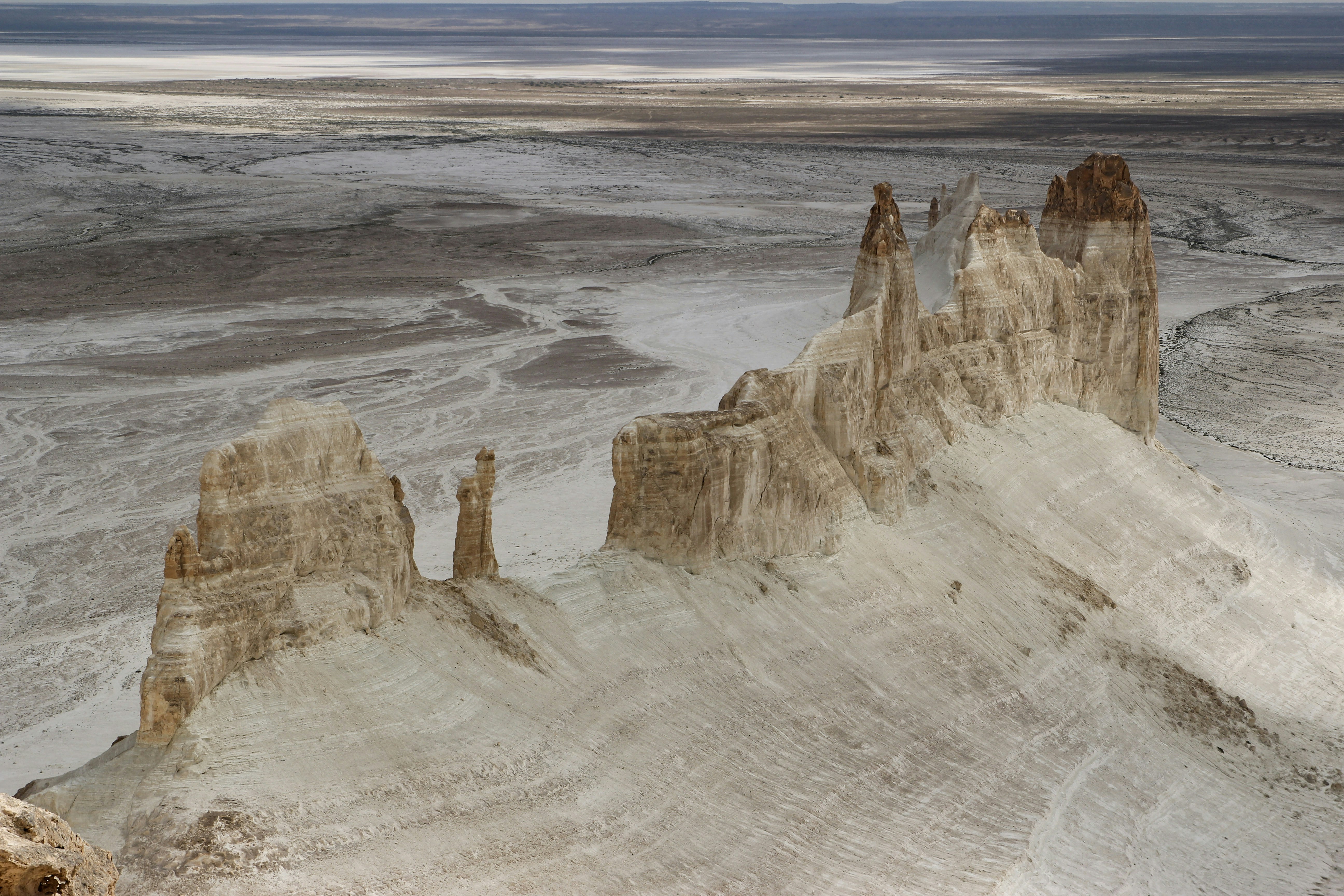 Majestic rock formations rise from a desolate landscape, showcasing nature's artistry through erosion. The stark contrast of textures and colors highlights the geological history of the area.