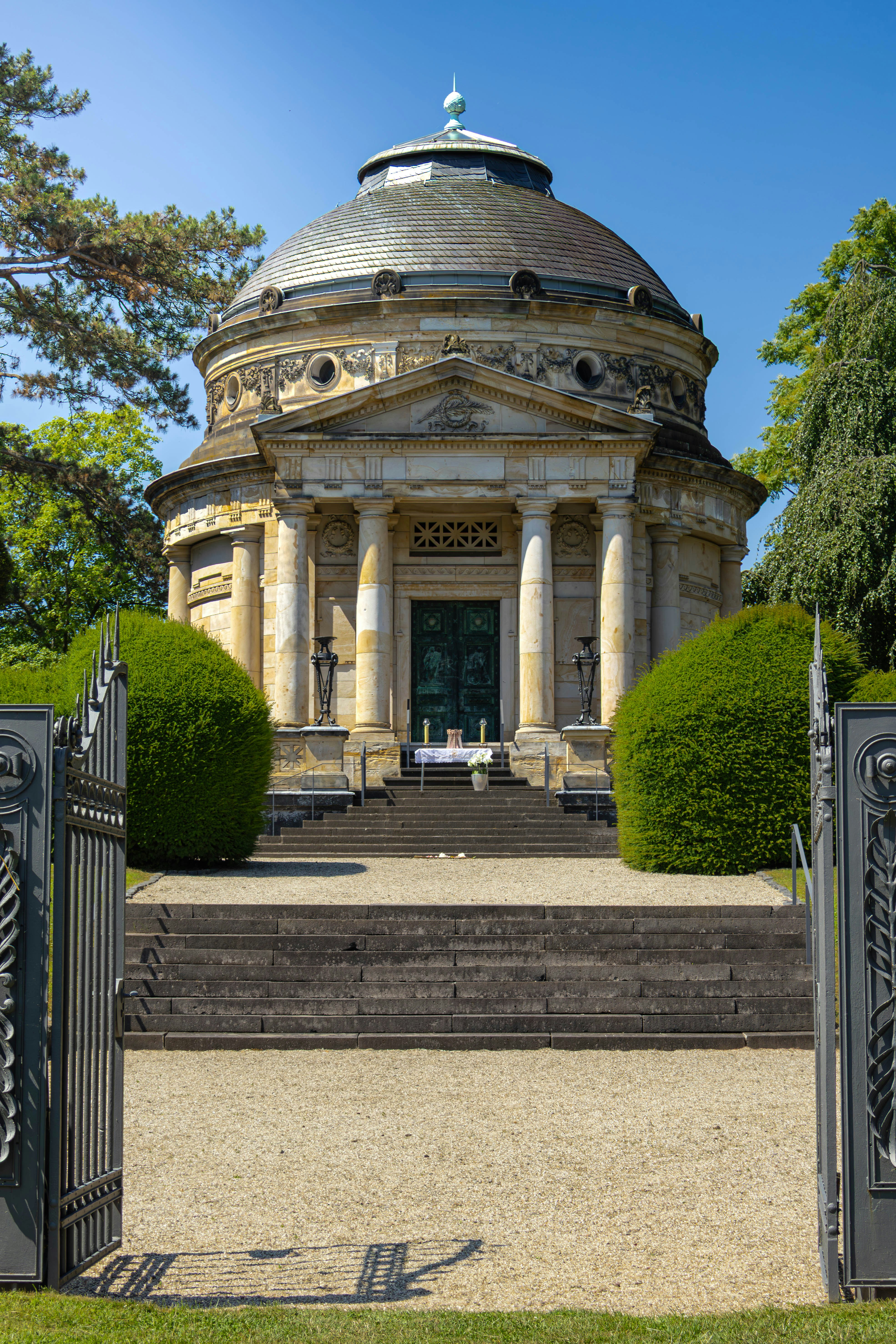 A grand neoclassical building sits beneath a bright sky.