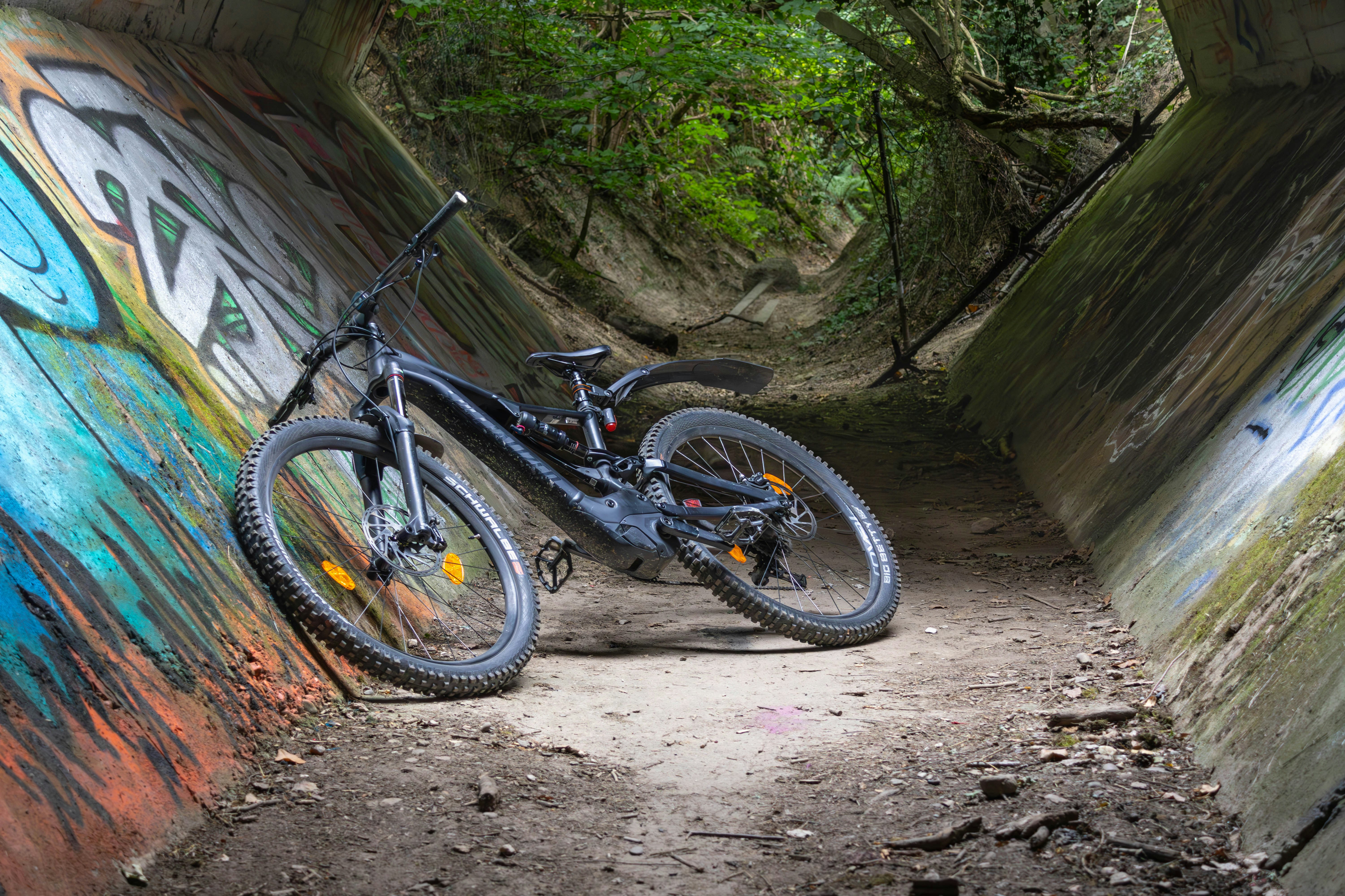 A mountain bike rests in a graffiti-filled tunnel.