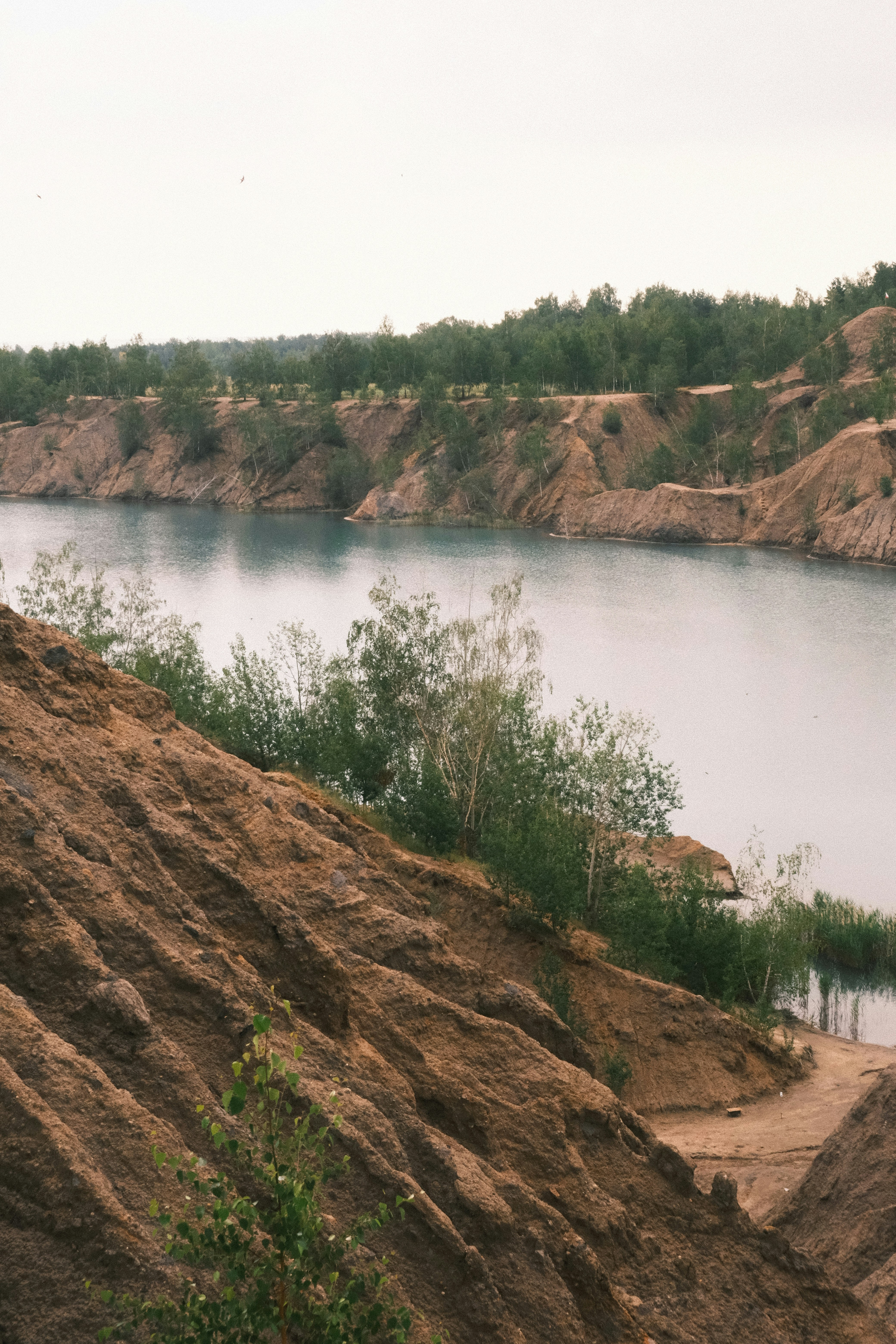 Sandy cliffs border a calm, blue lake.