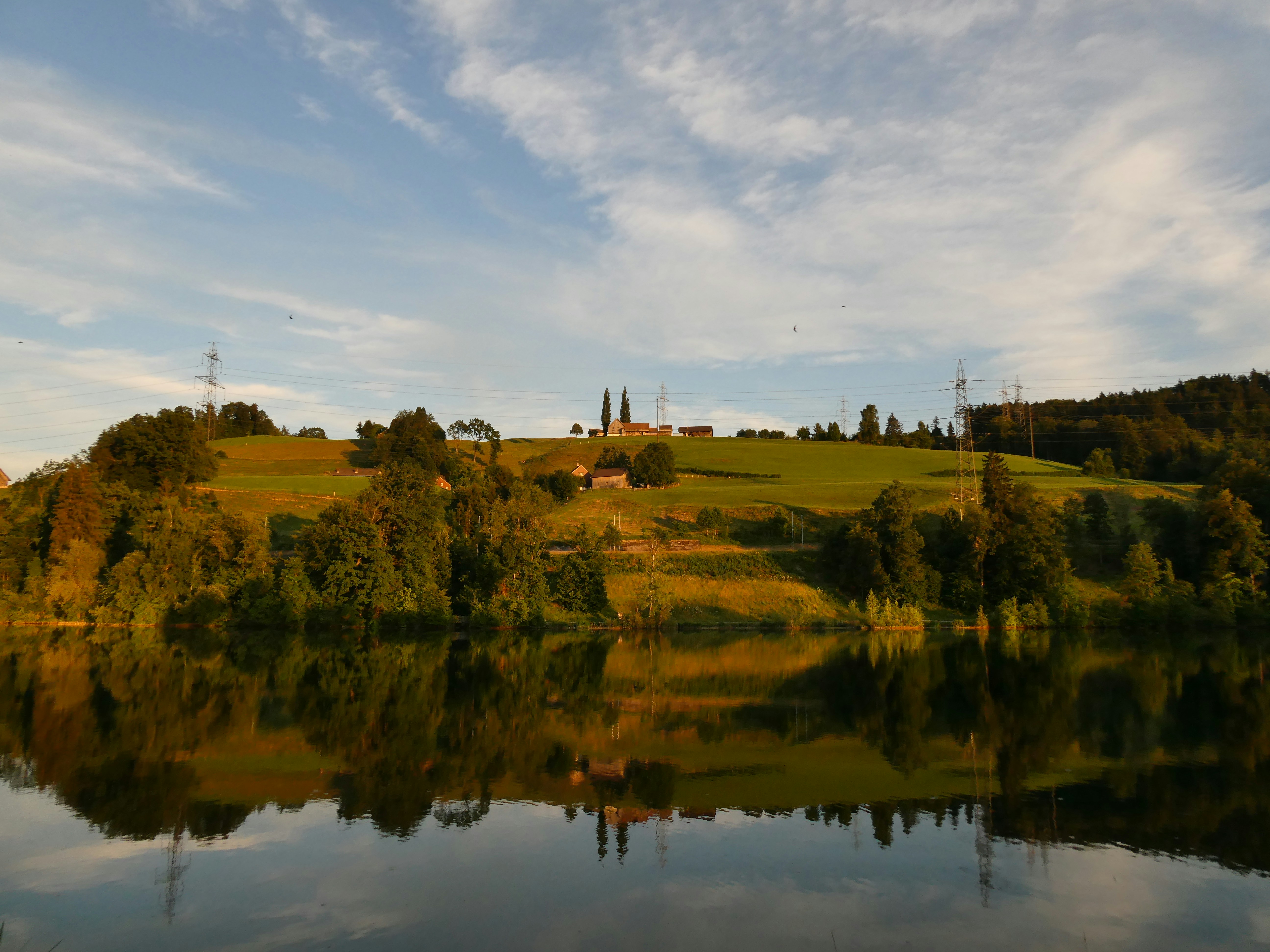 Sunday evening walk at Gübsensee, St.Gallen. | A lake reflects the distant hill and sky.