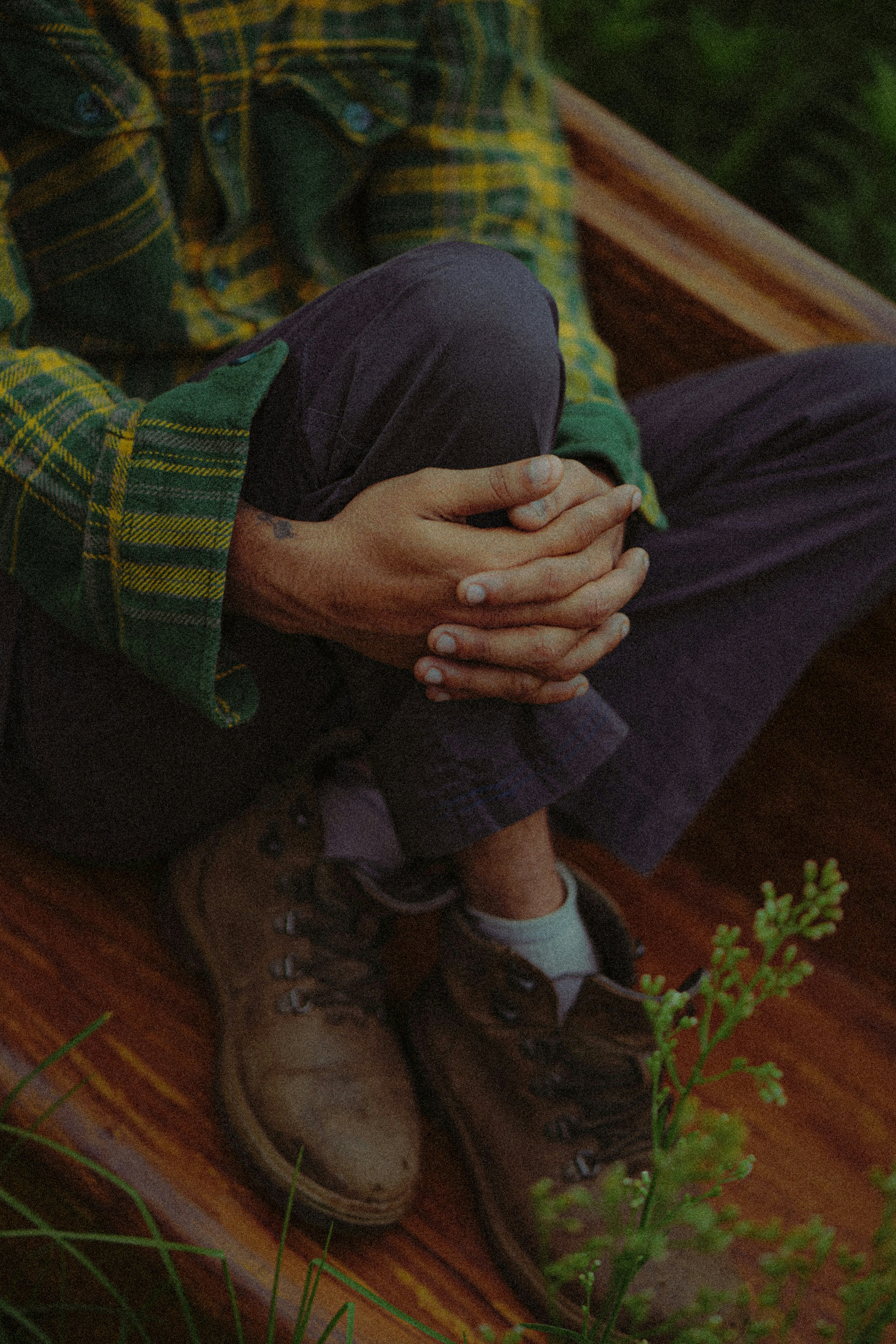 A person sits in a boat wearing boots.