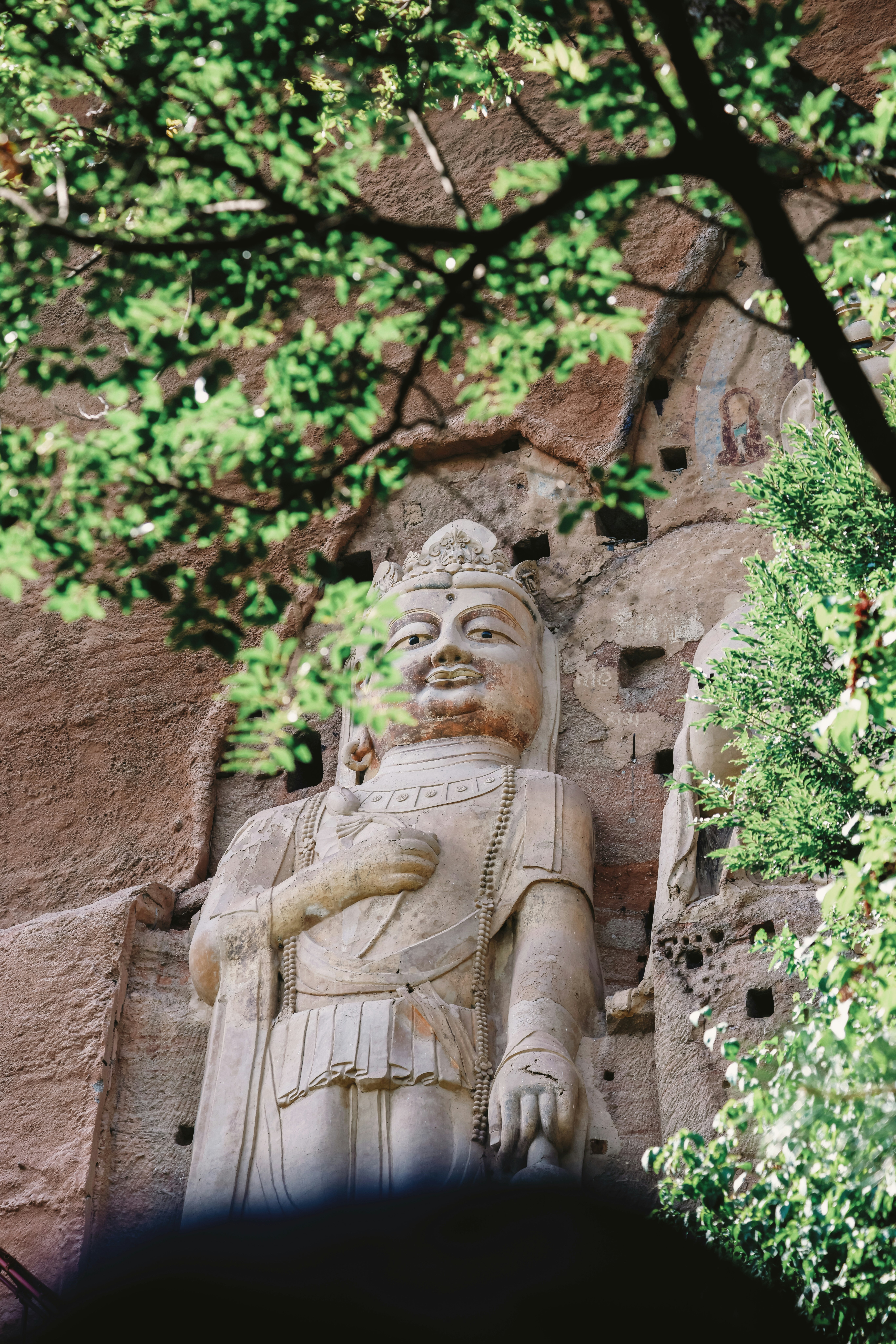 Created with RNI Films app. Profile 'Agfa Optima 200 Warm' | Buddha statue carved into a rock face.