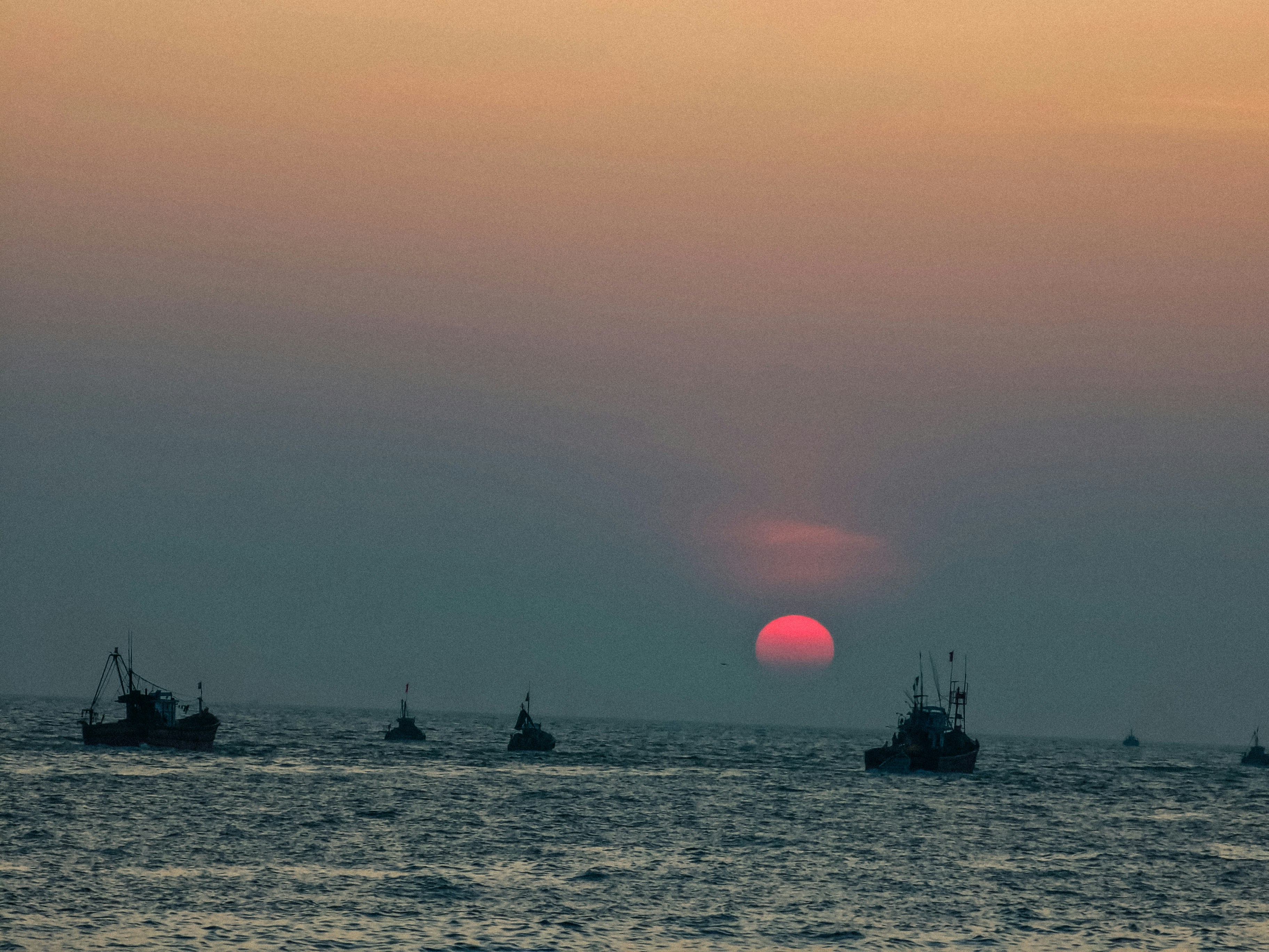 Fishing boats sailing into the sunset | Boats sail on the sea at sunset.
