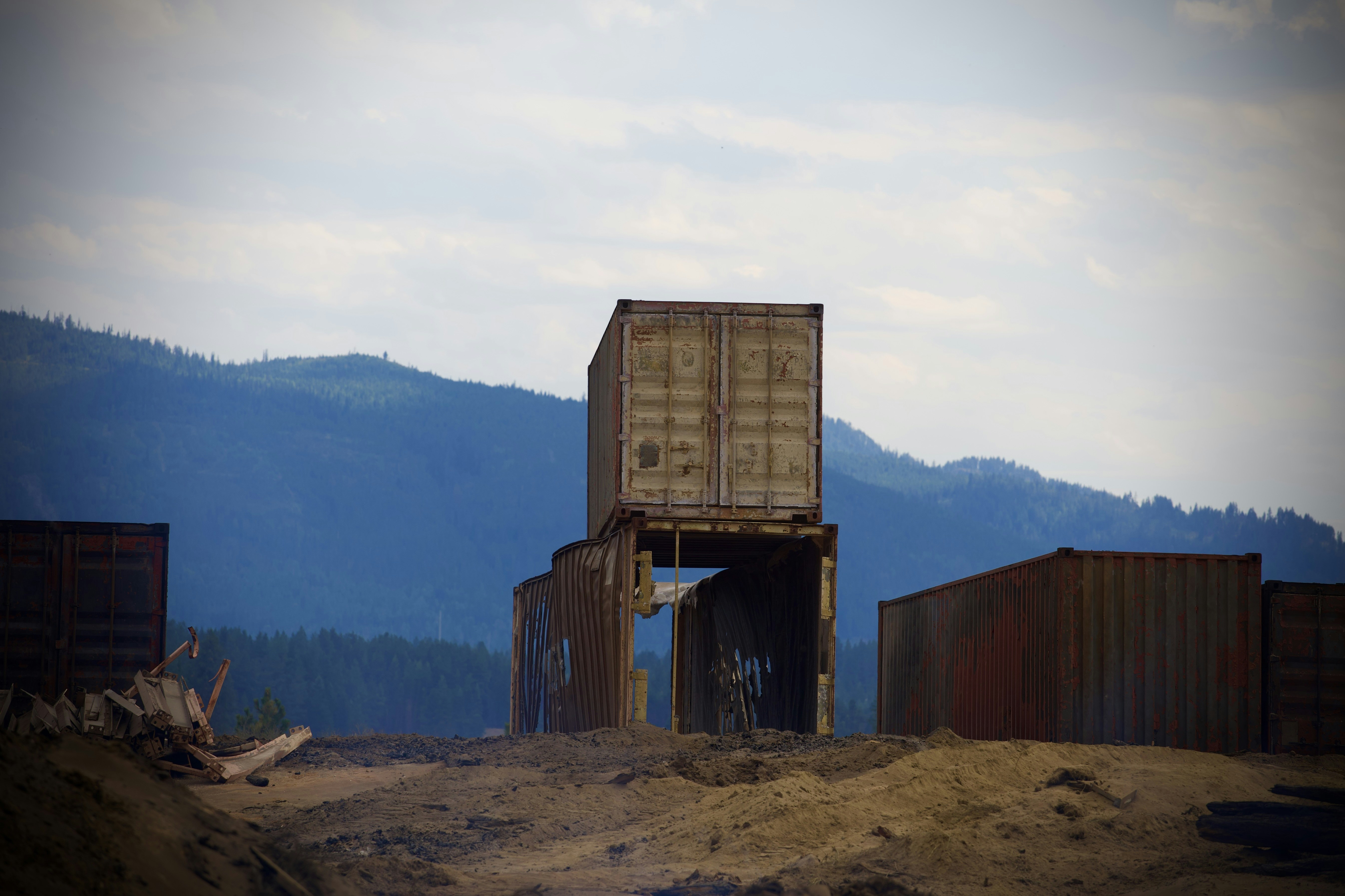 Shipping containers are stacked in a landscape.