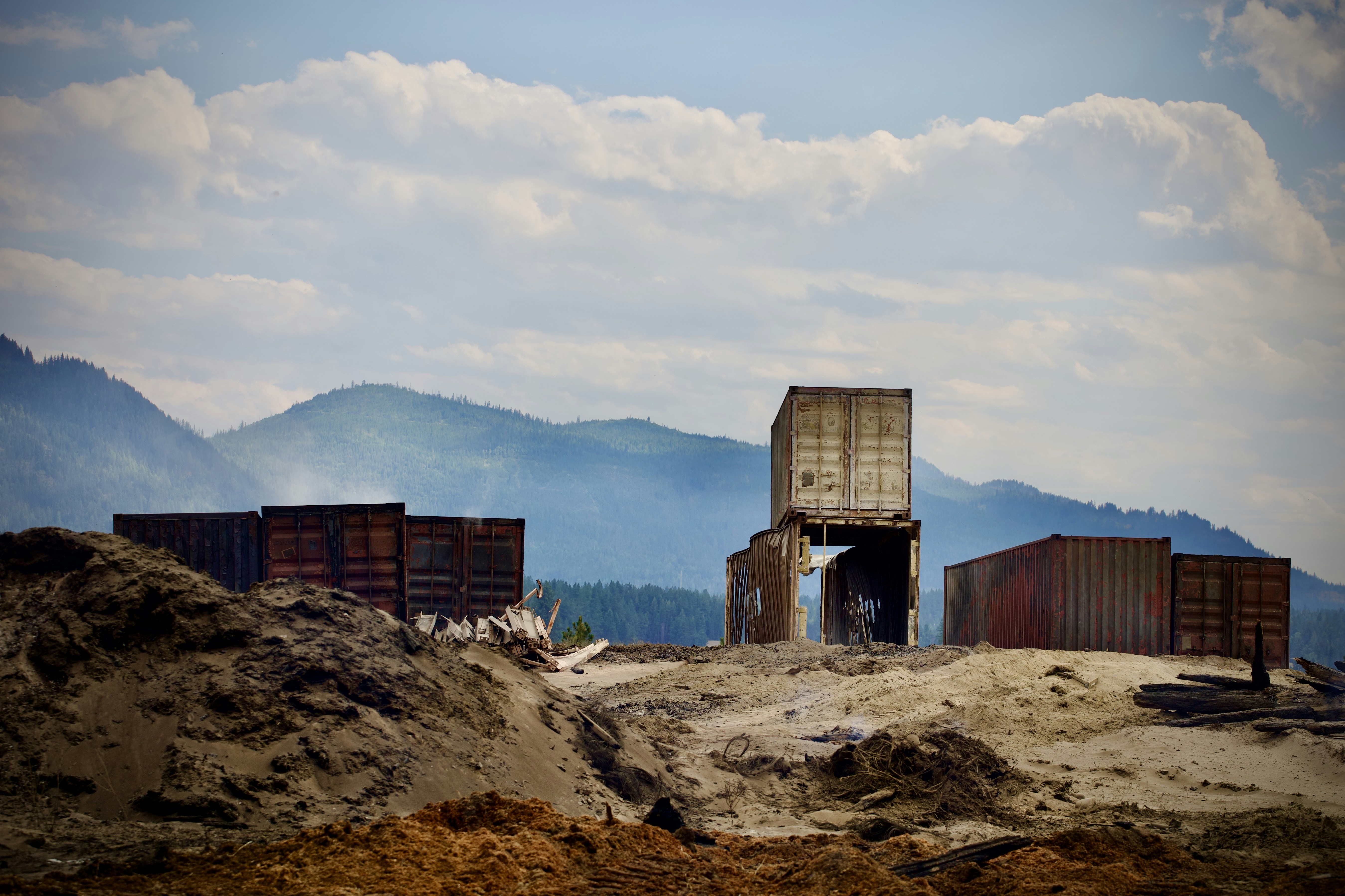 Shipping containers sit on a landscape with mountains.
