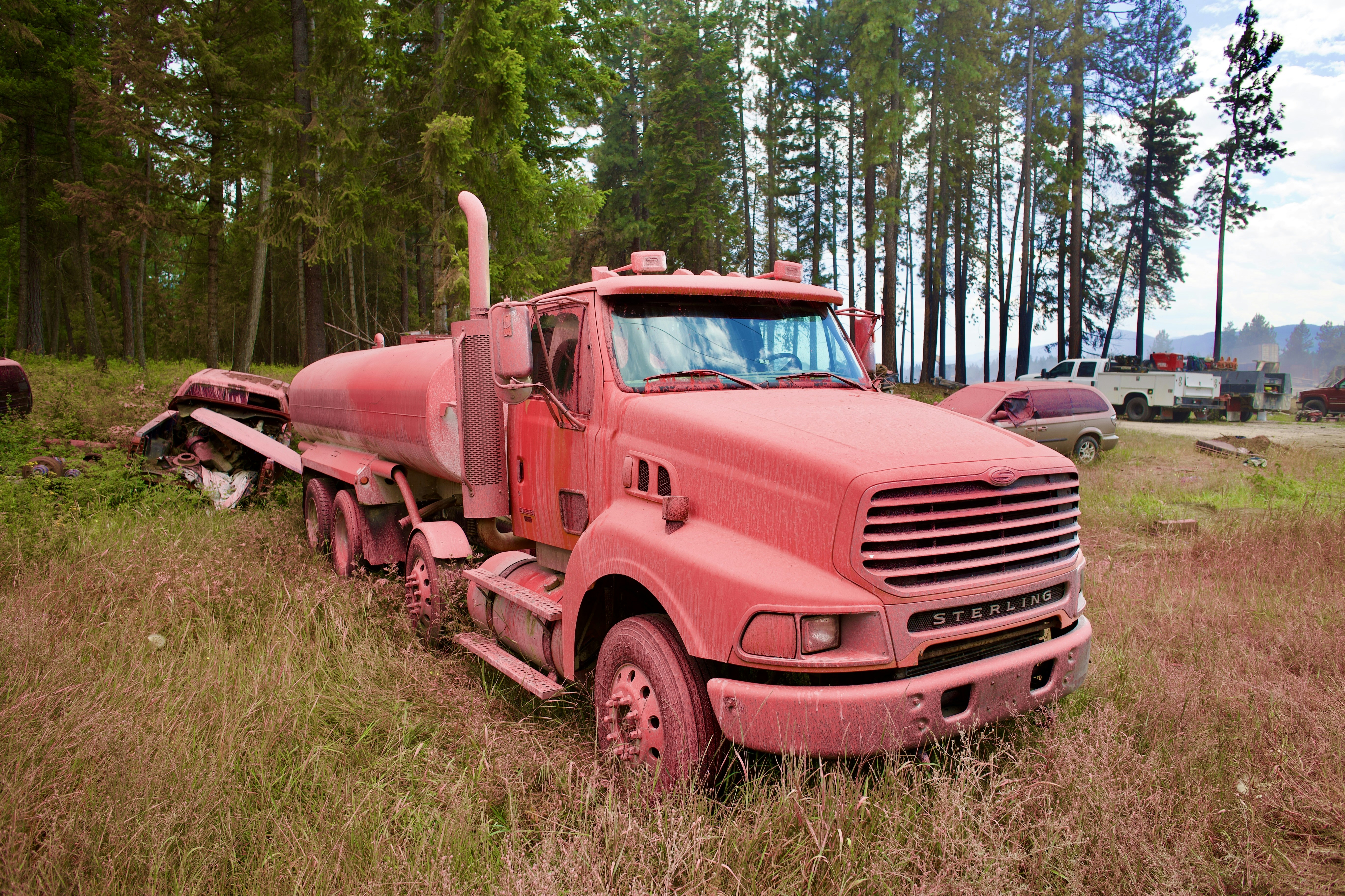 A red truck is parked in a grassy field.