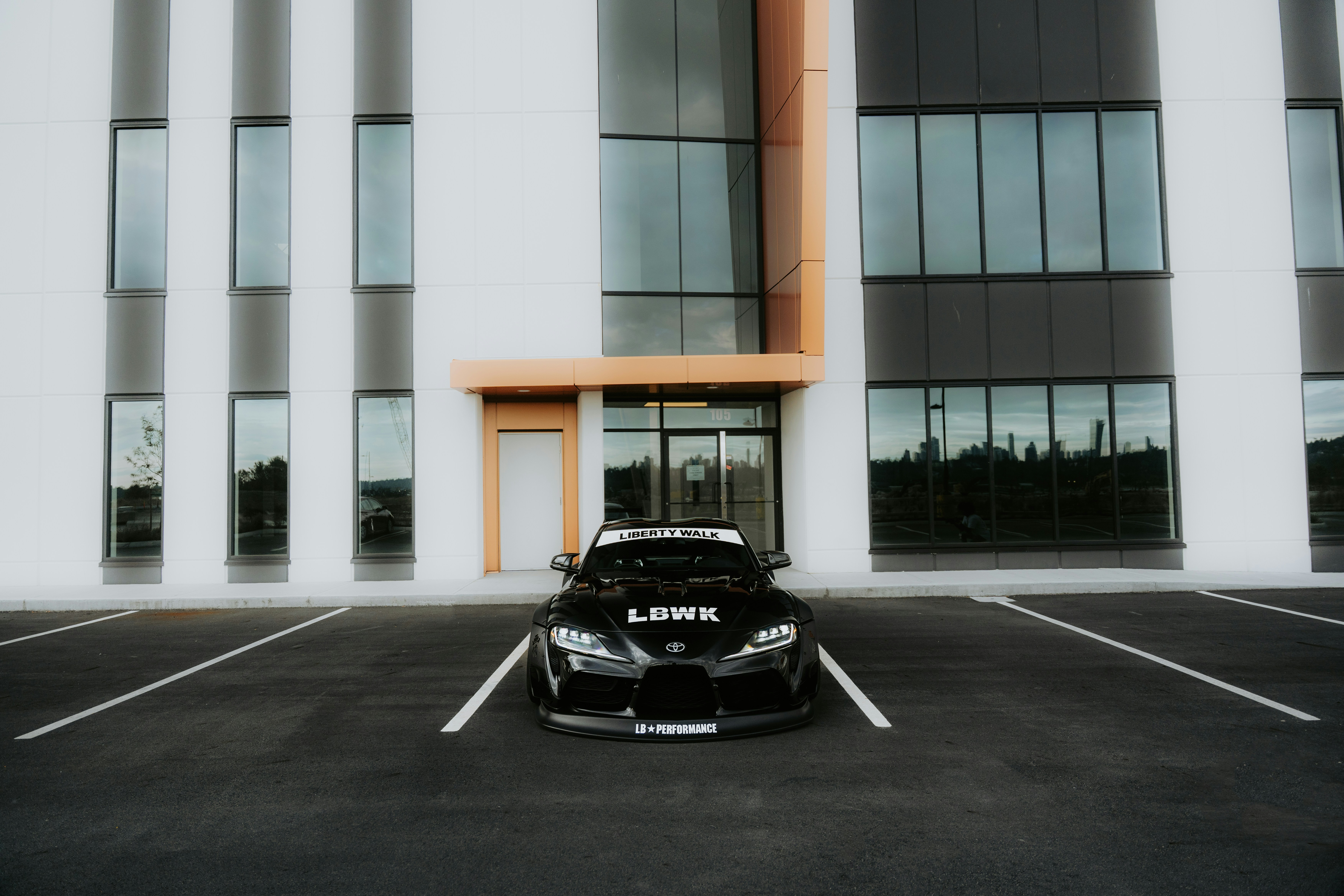 A black car is parked in front of a building.