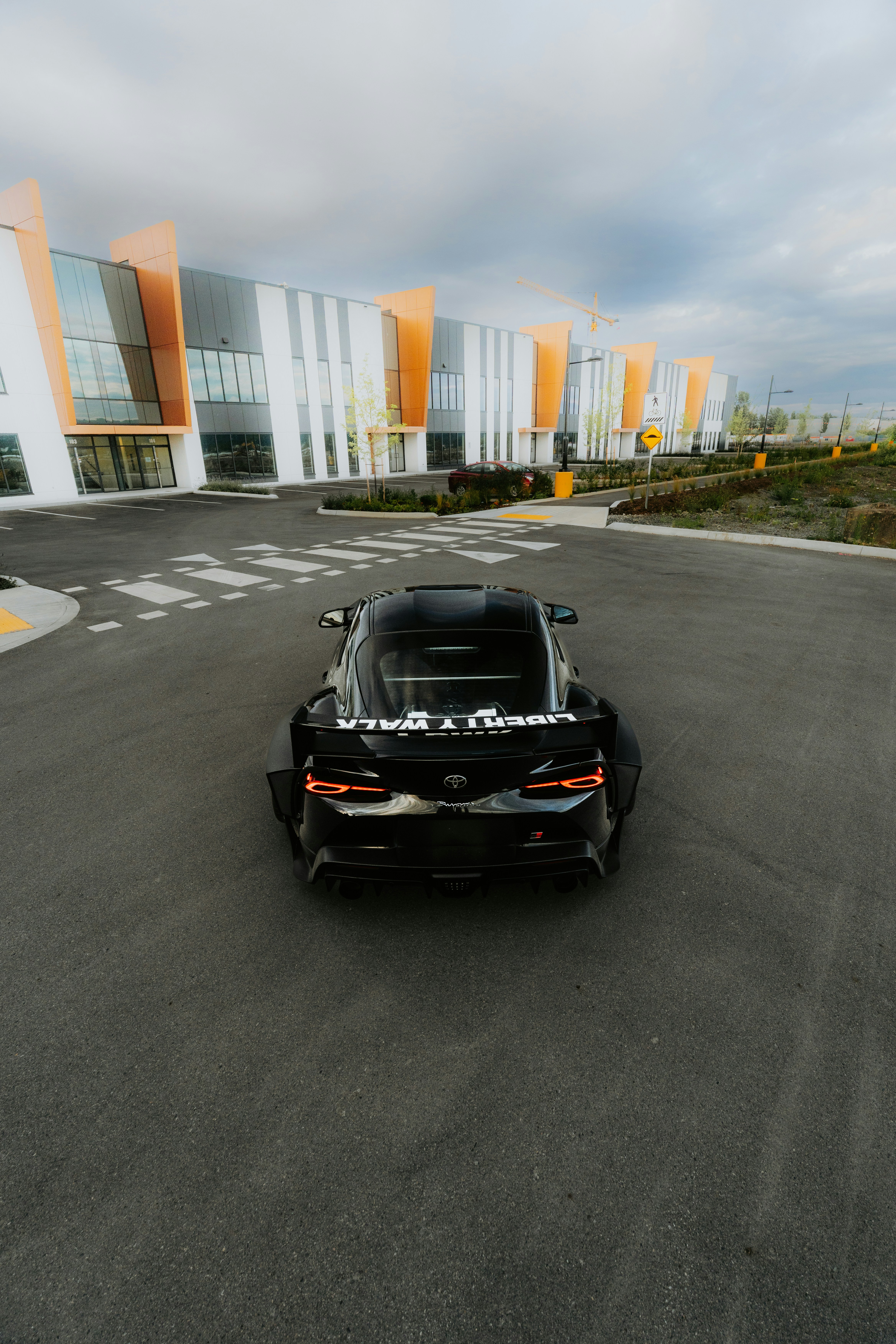 Sleek black sports car parked in front of a contemporary building, showcasing its aerodynamic design and bold branding.