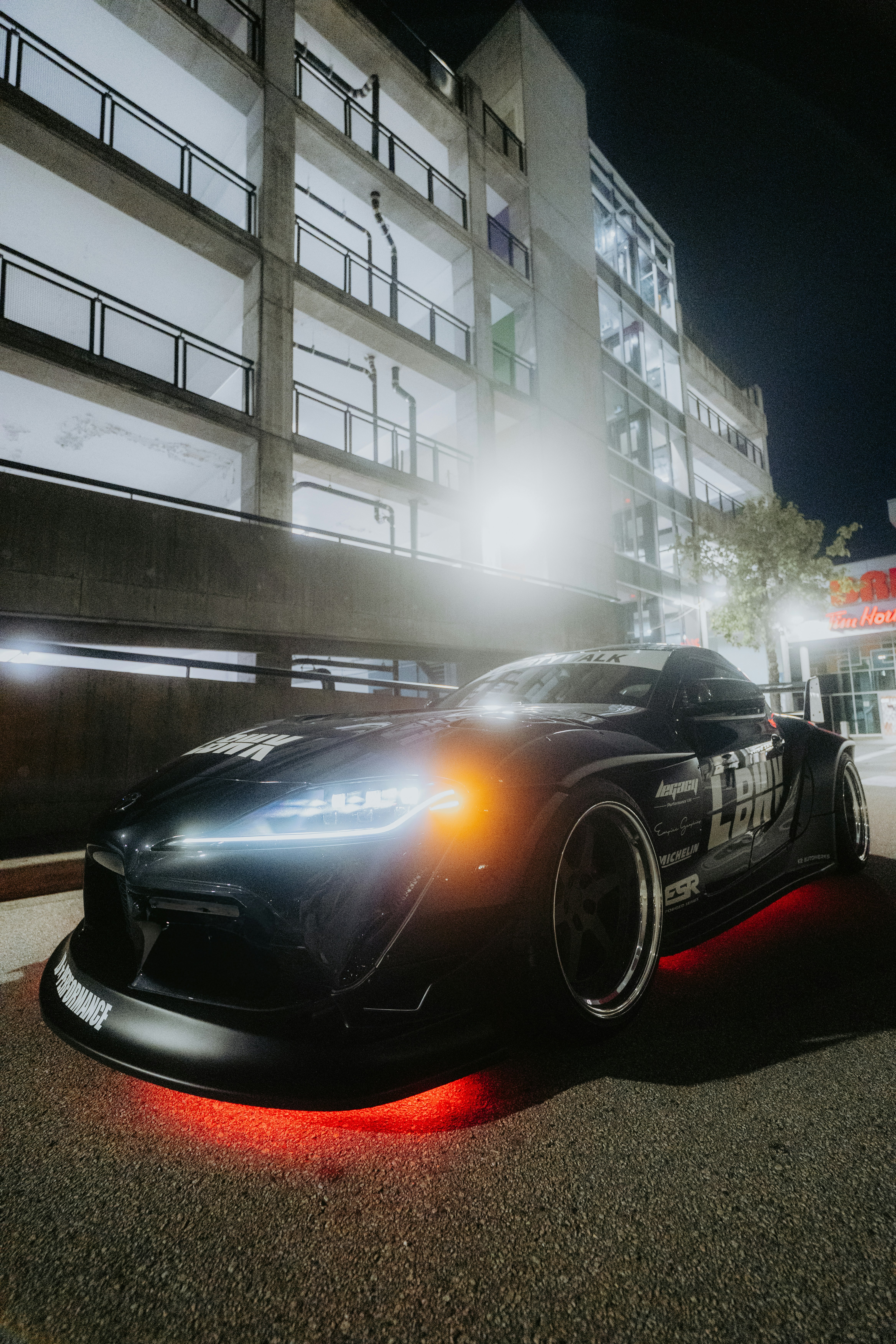 A black sports car is illuminated at night.