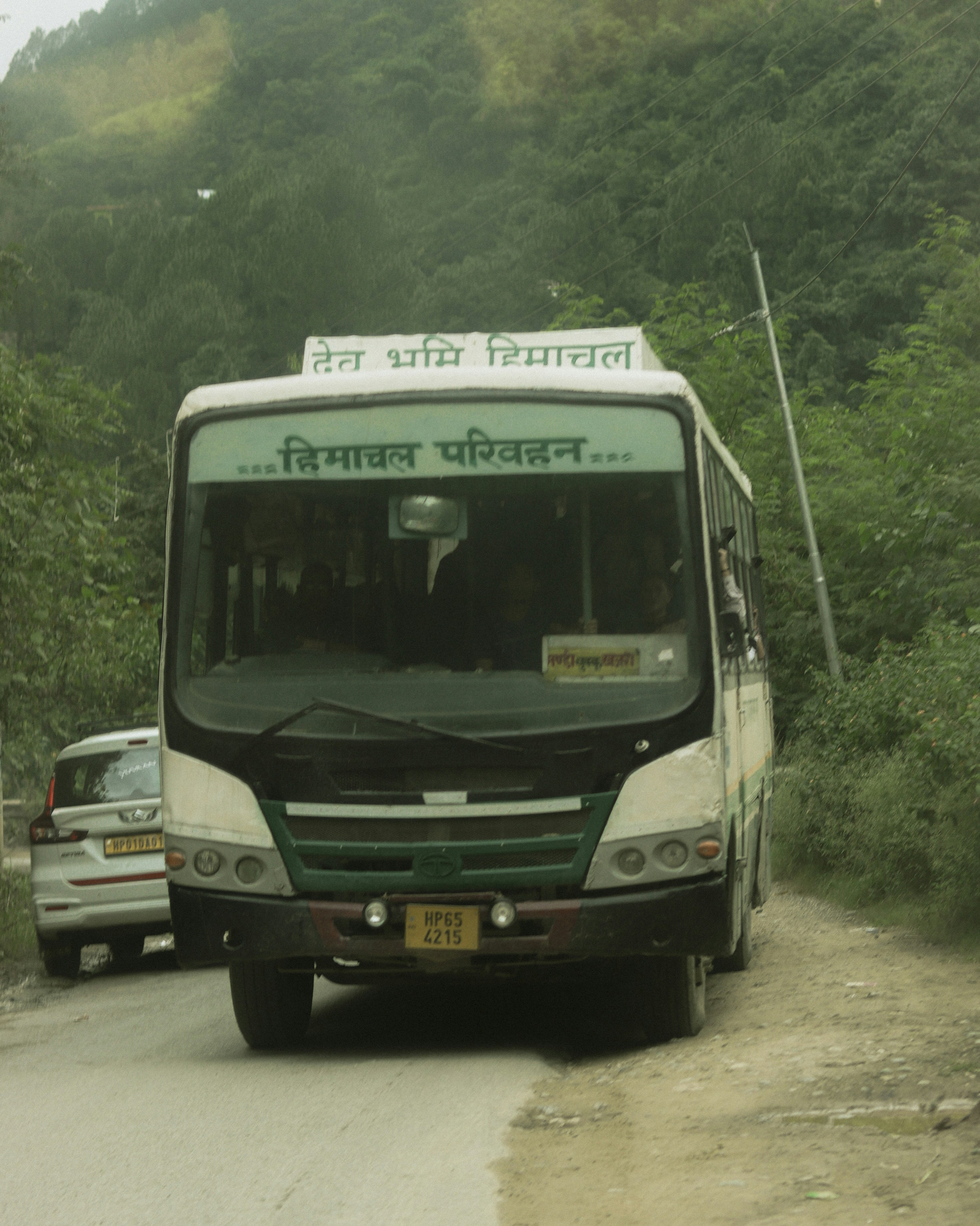 Hrtc Bus | A bus travels down a mountain road.