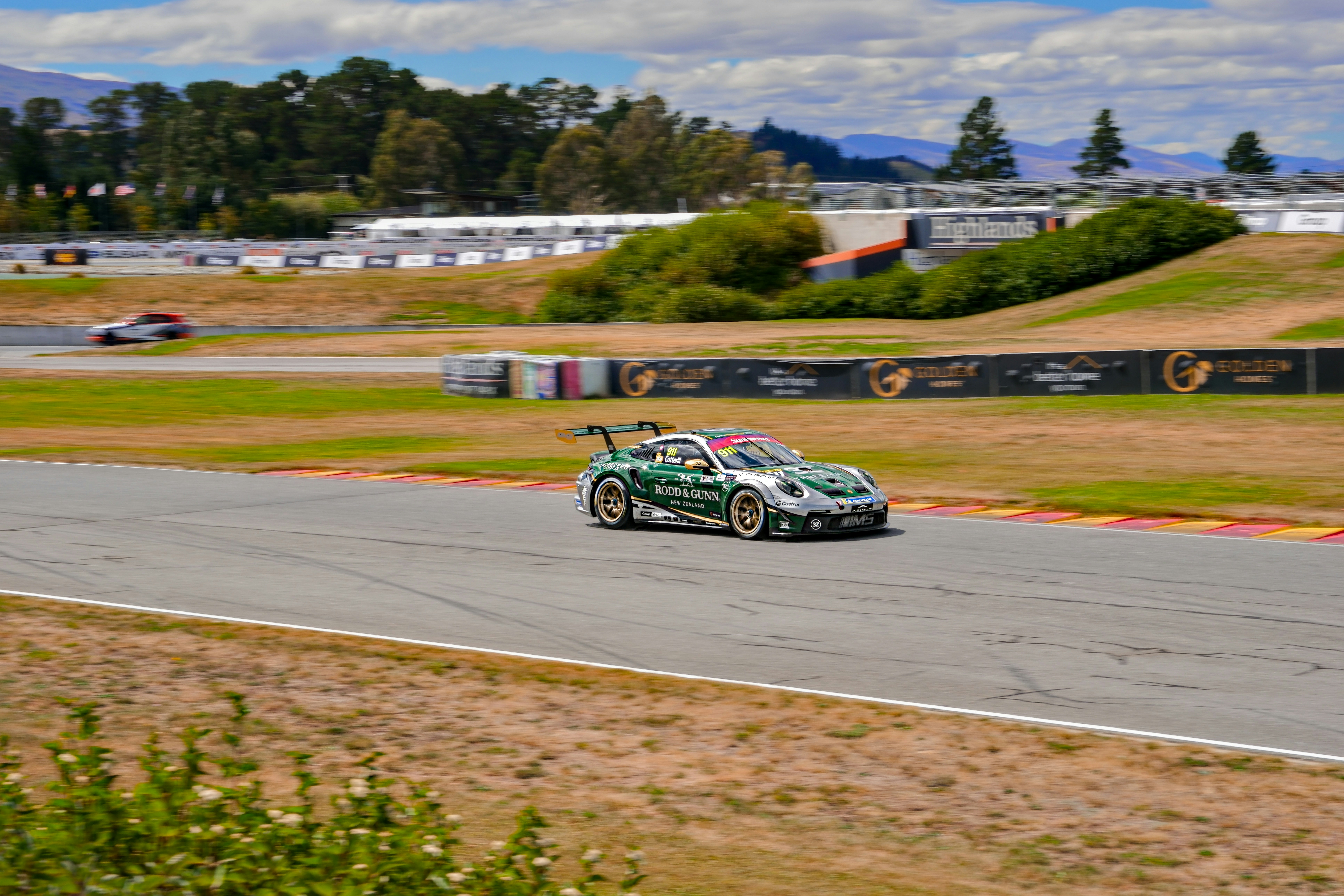 Verdant-green race car carves a sunlit line through a curving track