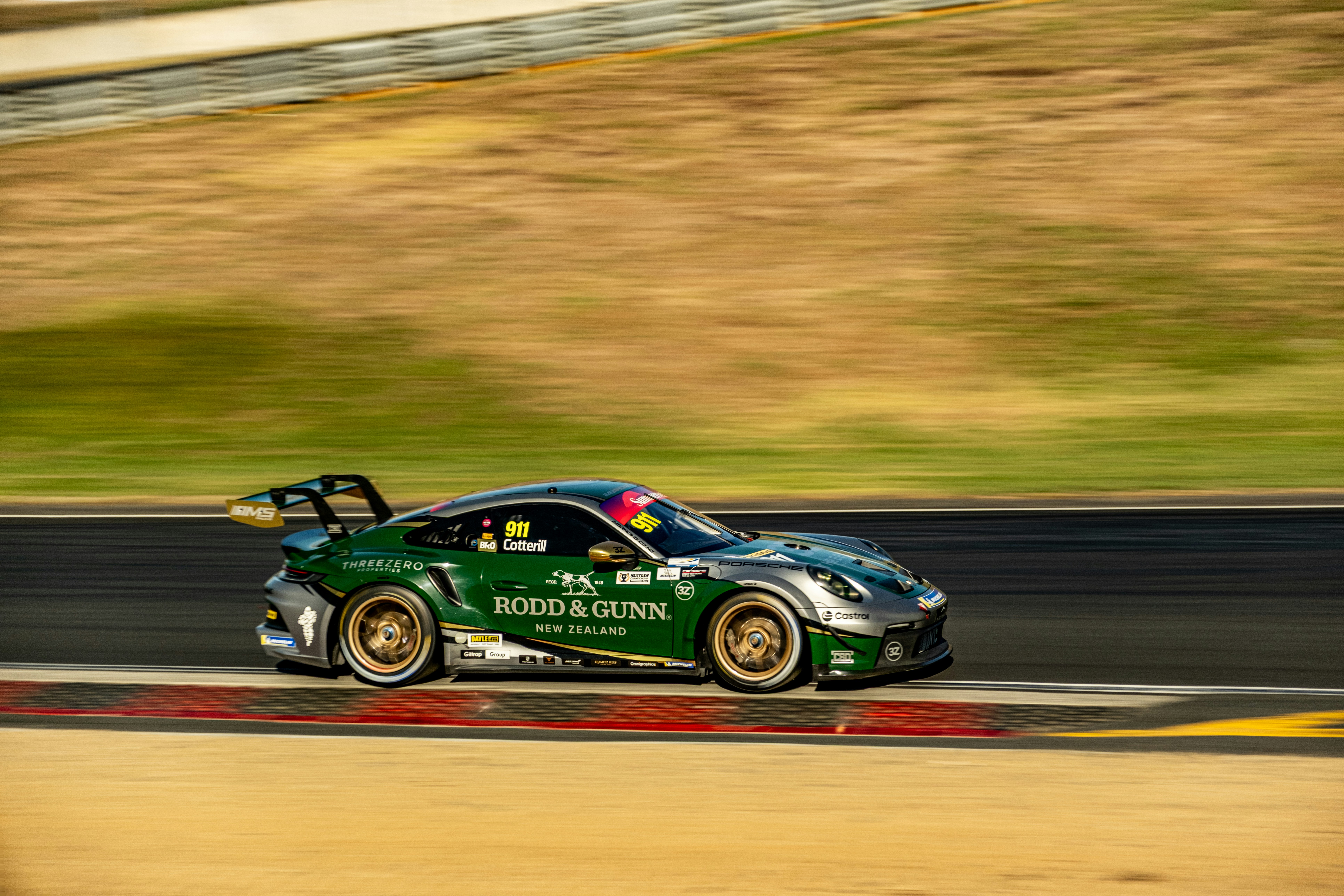 A green race car speeds along a track.