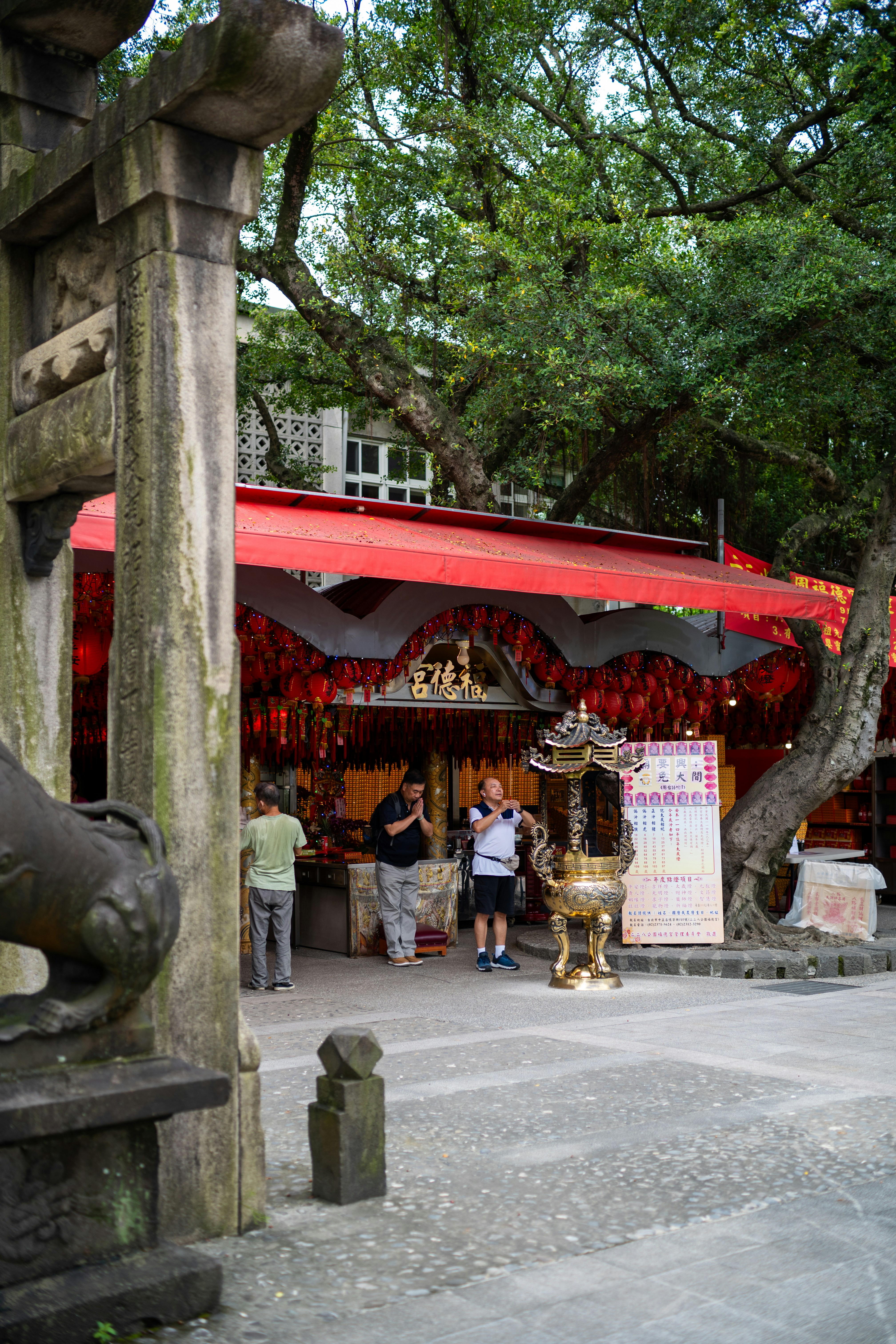 People pray at a temple outside, among the trees. photo – Free City ...