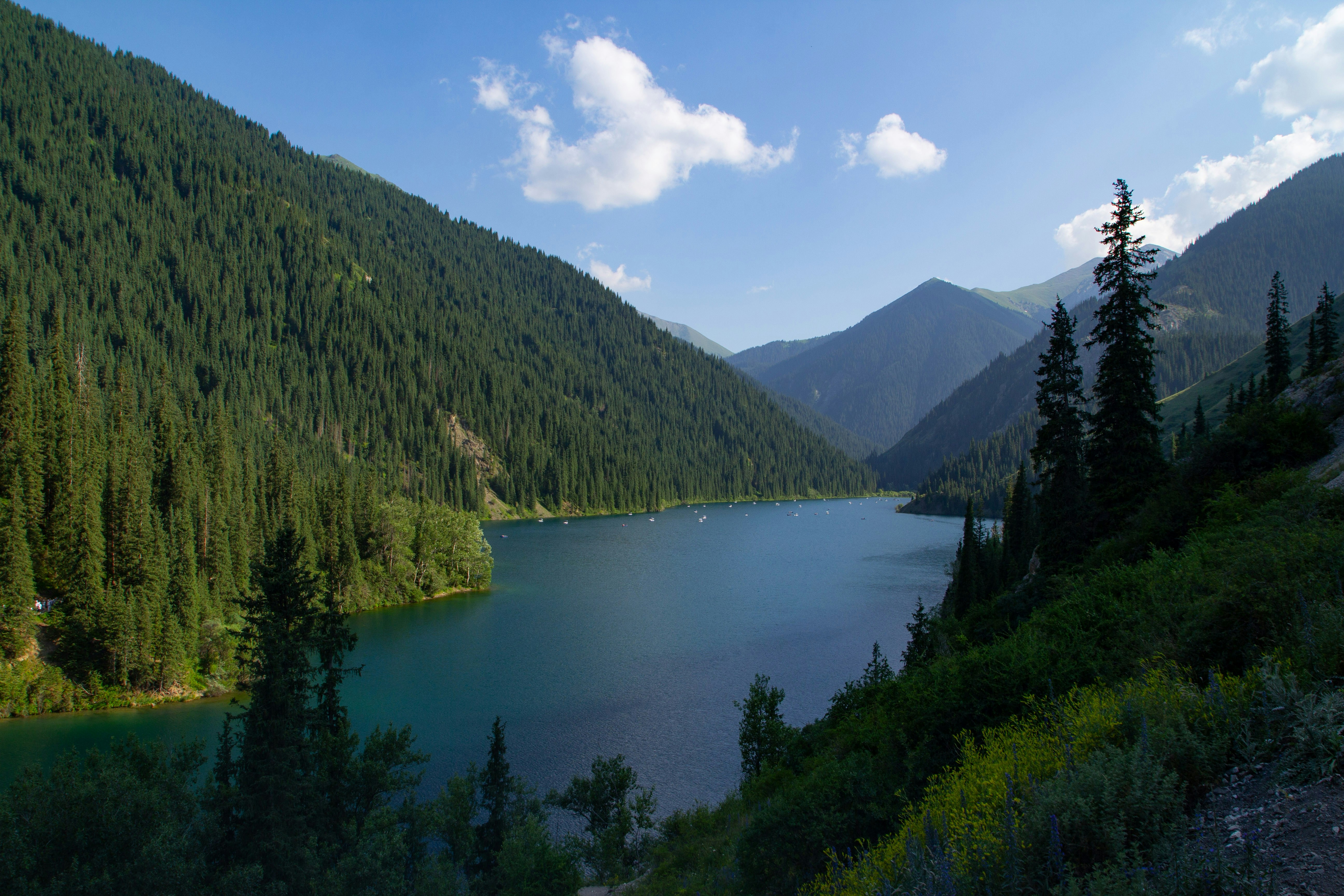 Serene lake nestled between towering mountains and lush forests, reflecting the vibrant colors of nature. Perfectly captures the tranquility of the wilderness.