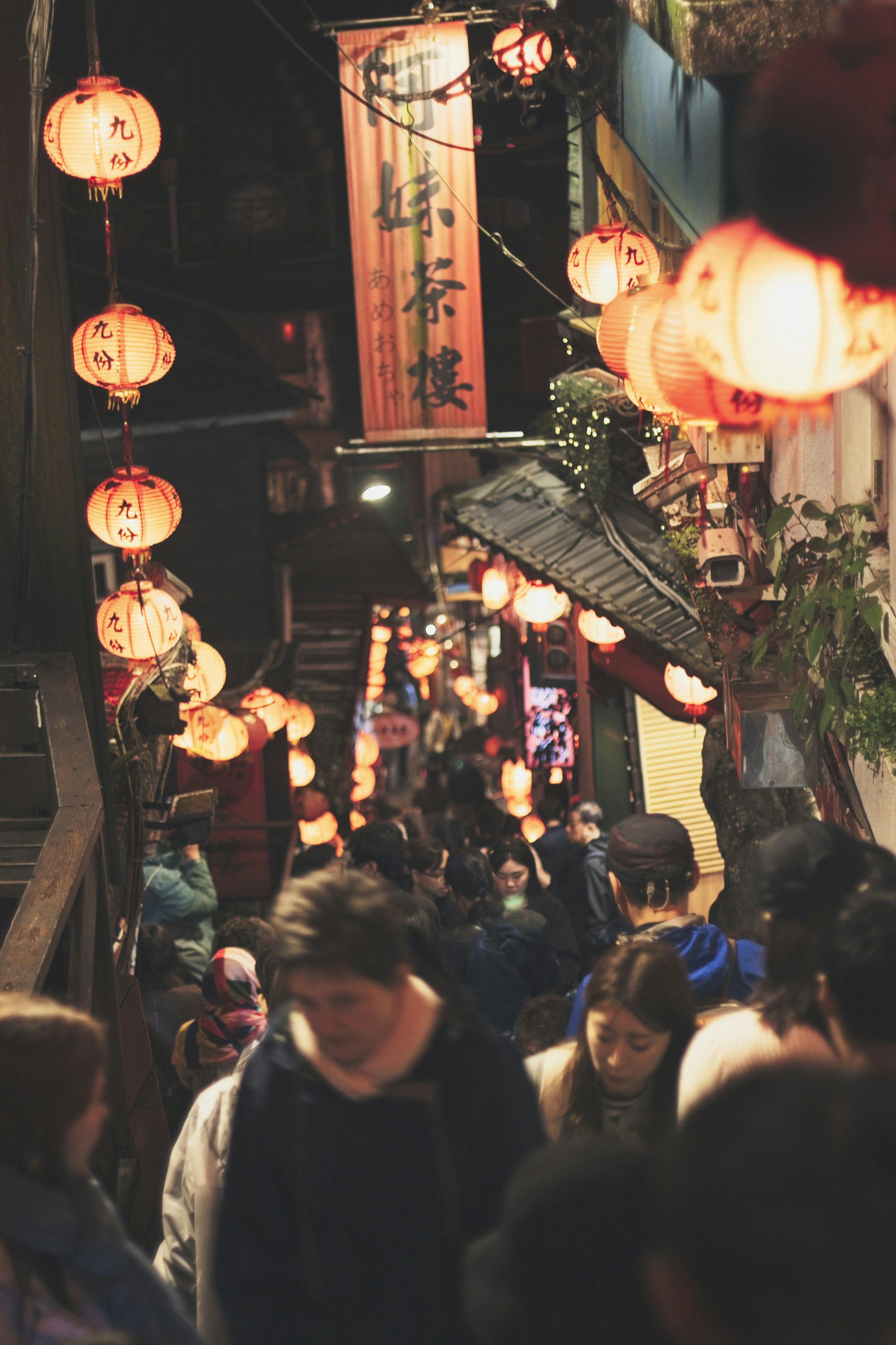 Crowded street adorned with glowing lanterns, leading through a historic district at night. The vibrant atmosphere reflects local culture and community.