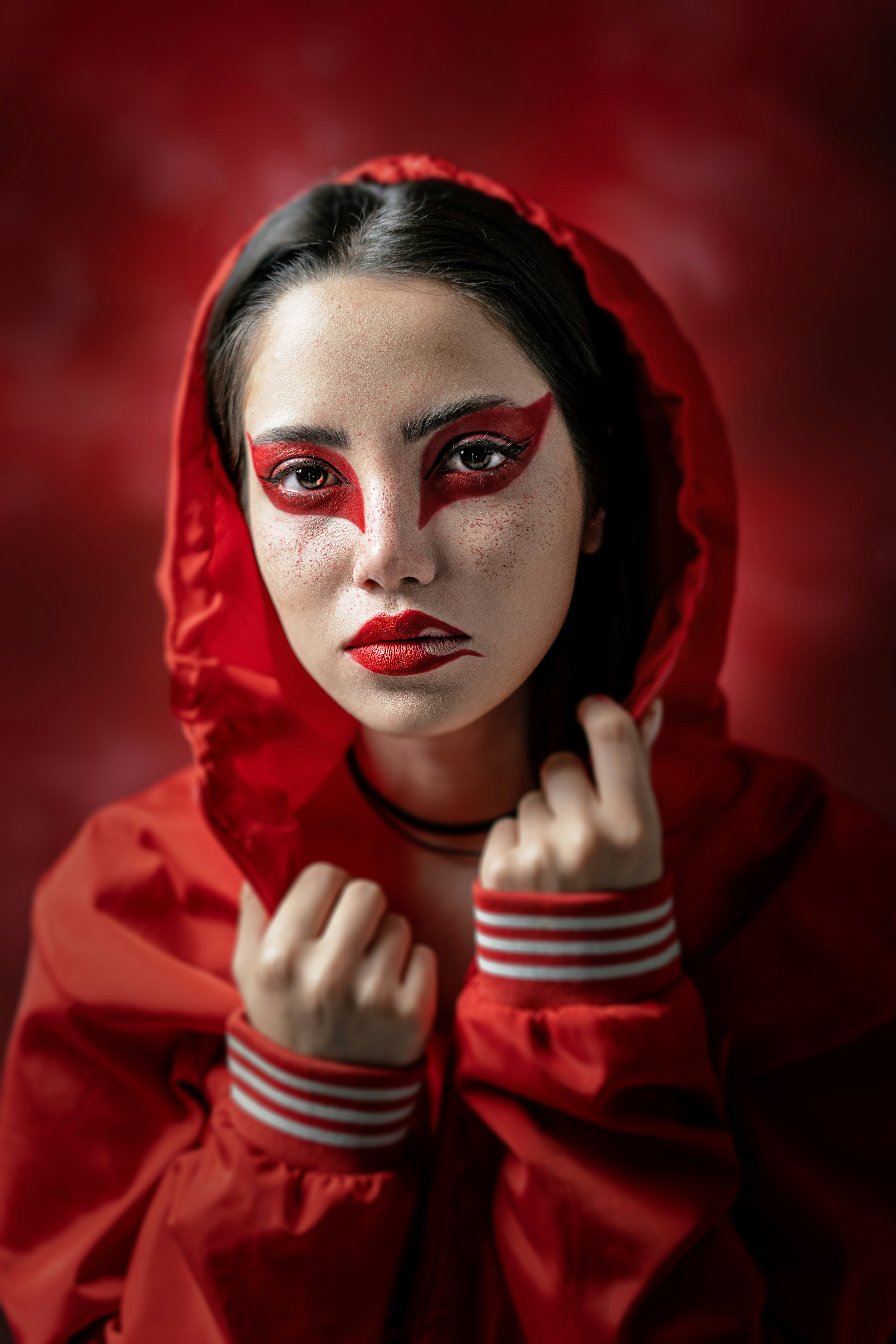 A woman poses in a red outfit and makeup.