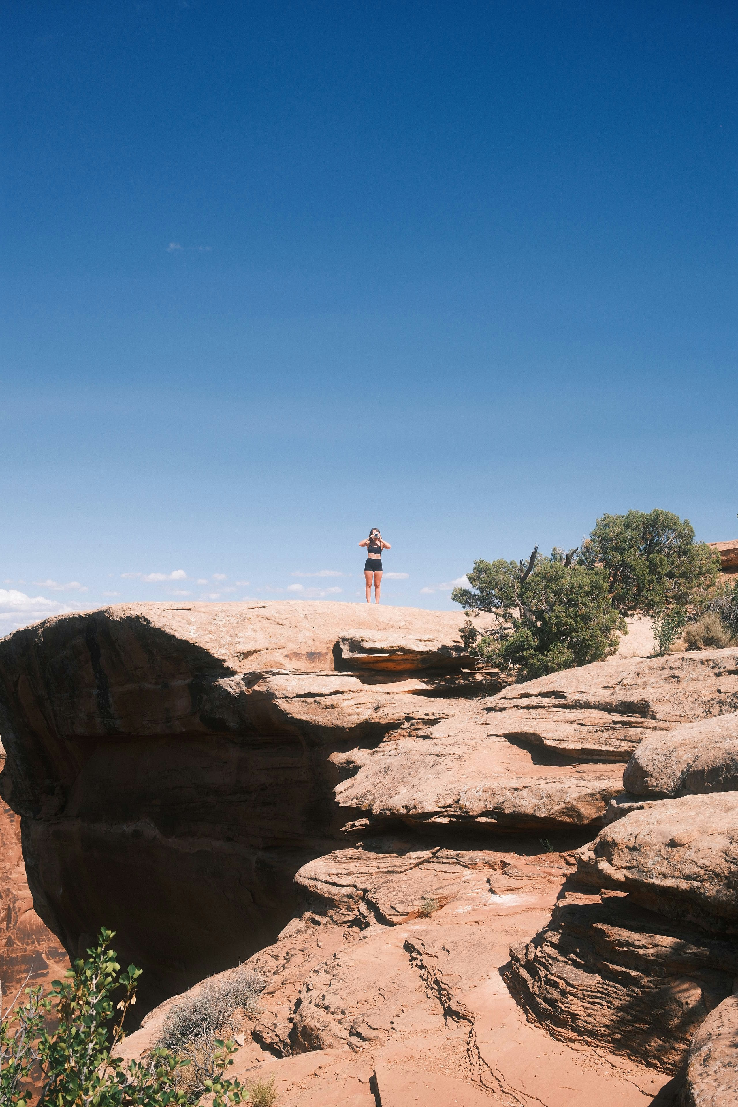 @Lgnwvr | Lgnwvr.com | Person stands on a desert cliff under a blue sky.