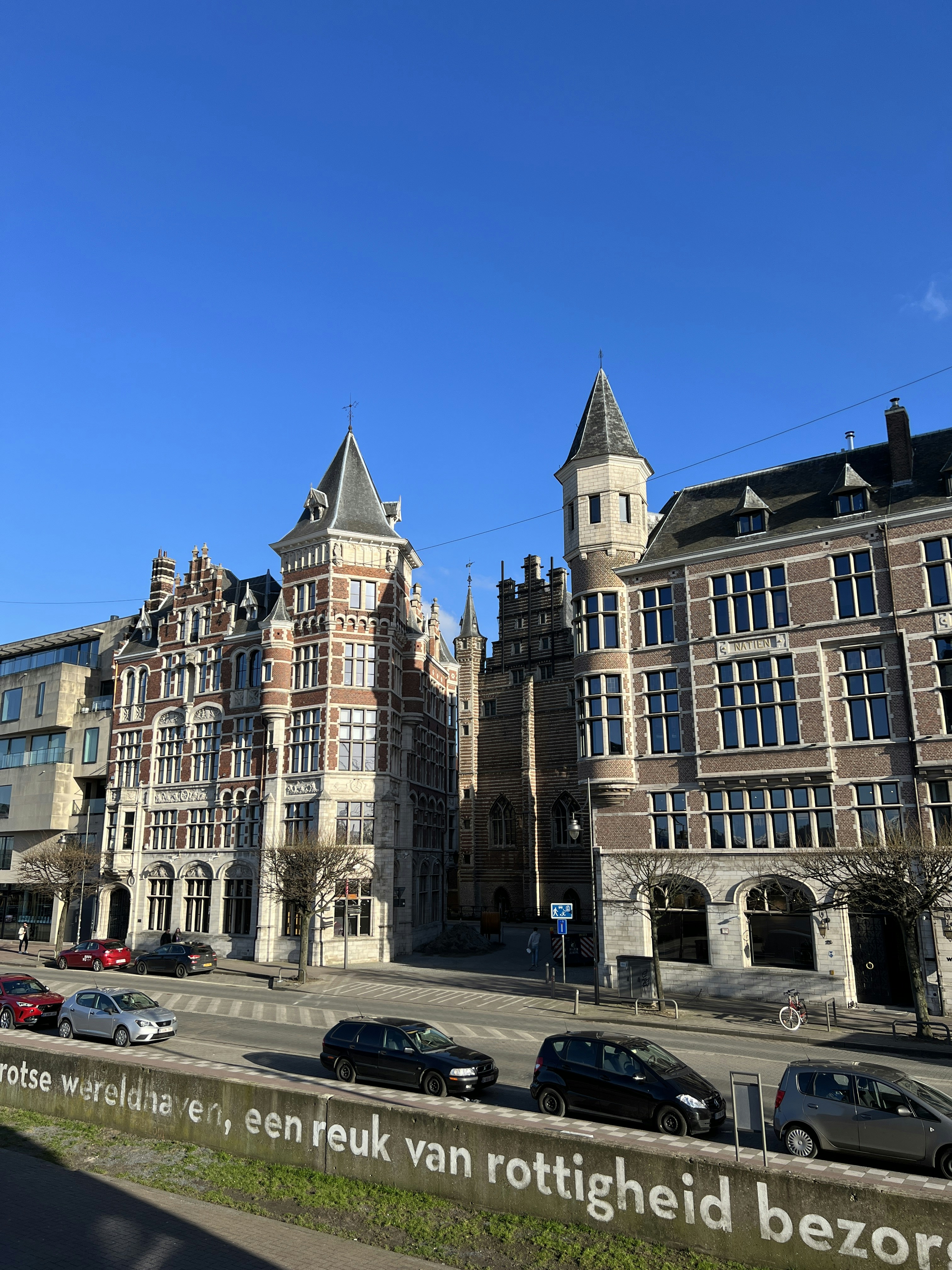 This majestic clock-tower dominates the vibrant Grote Markt in Antwerp's historic city center, its imposing presence a testament to the region's rich architectural heritage. | Beautiful european architecture on a bright, sunny day.