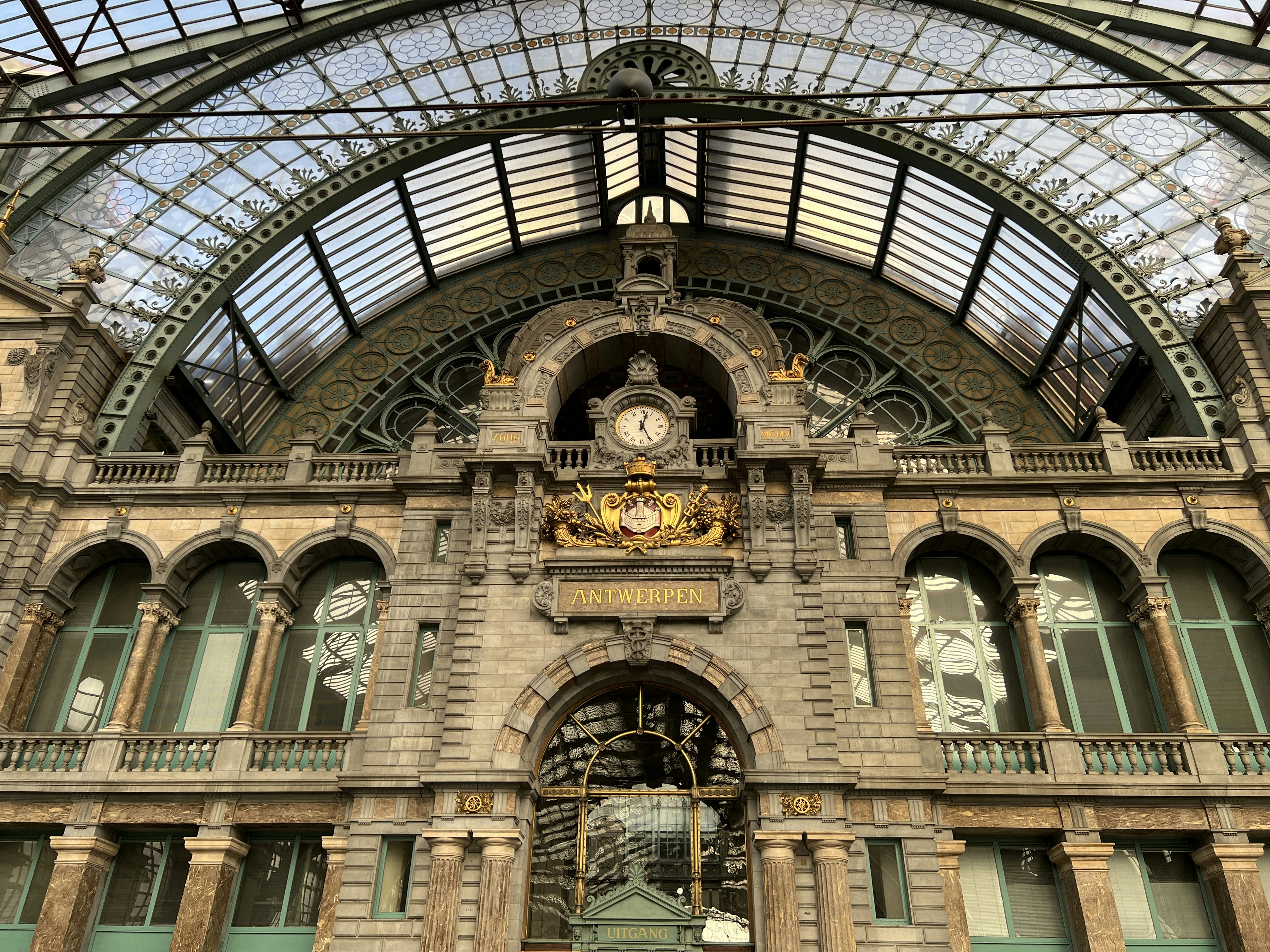 Grand facade of Antwerp Central Station showcasing intricate stonework and a striking glass roof.