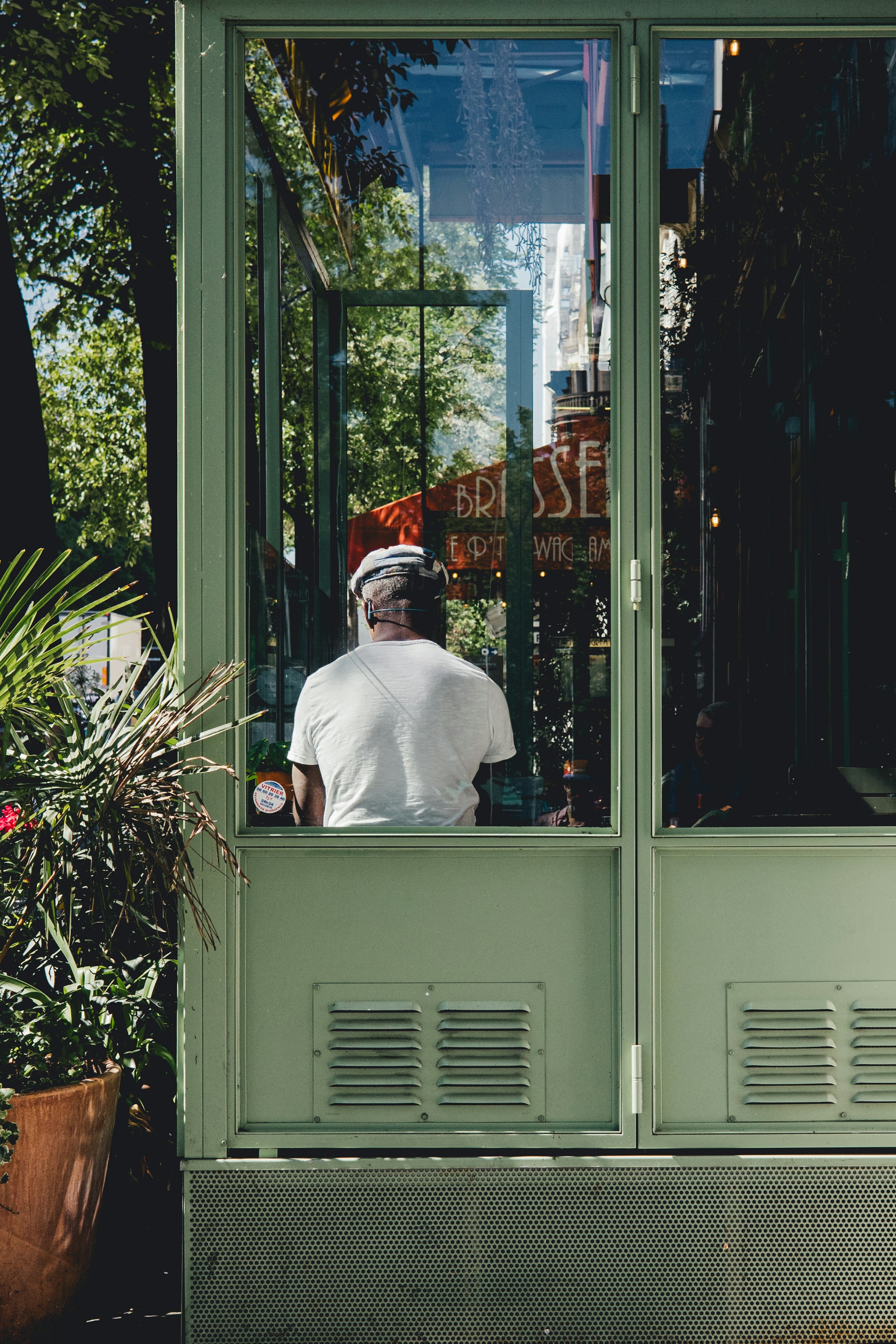 Behind the Glass: A Quiet Moment in Front of a Green Facade
