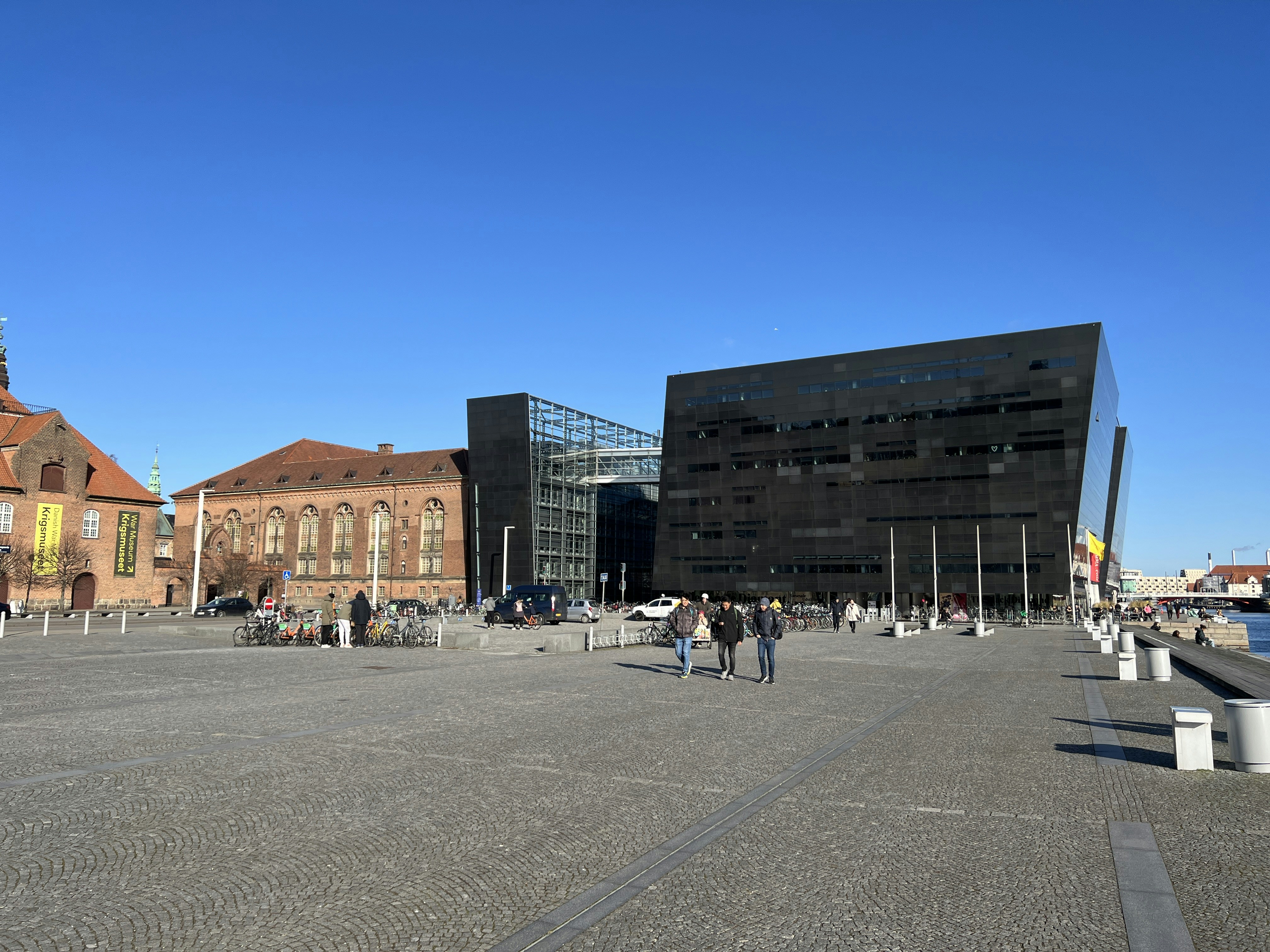 Grand urban structure with expansive glass facade dominating the Copenhagen waterfront. | A modern building stands in front of the blue sky.