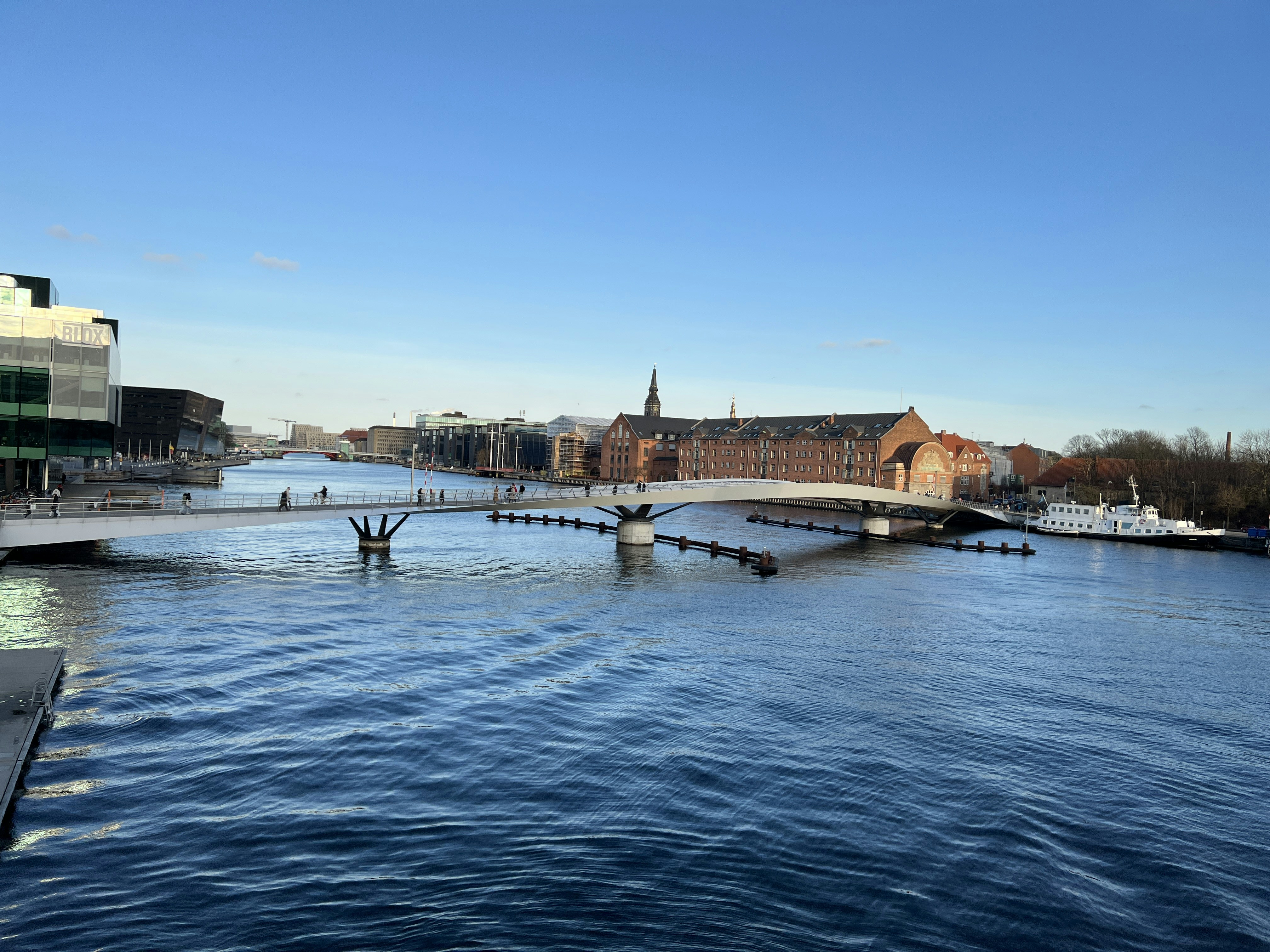 A serene reflection of Copenhagen's harbor waters, captured at the historic Langebro bridge in Kalvebod Brygge. | A scenic view of a bridge over water.
