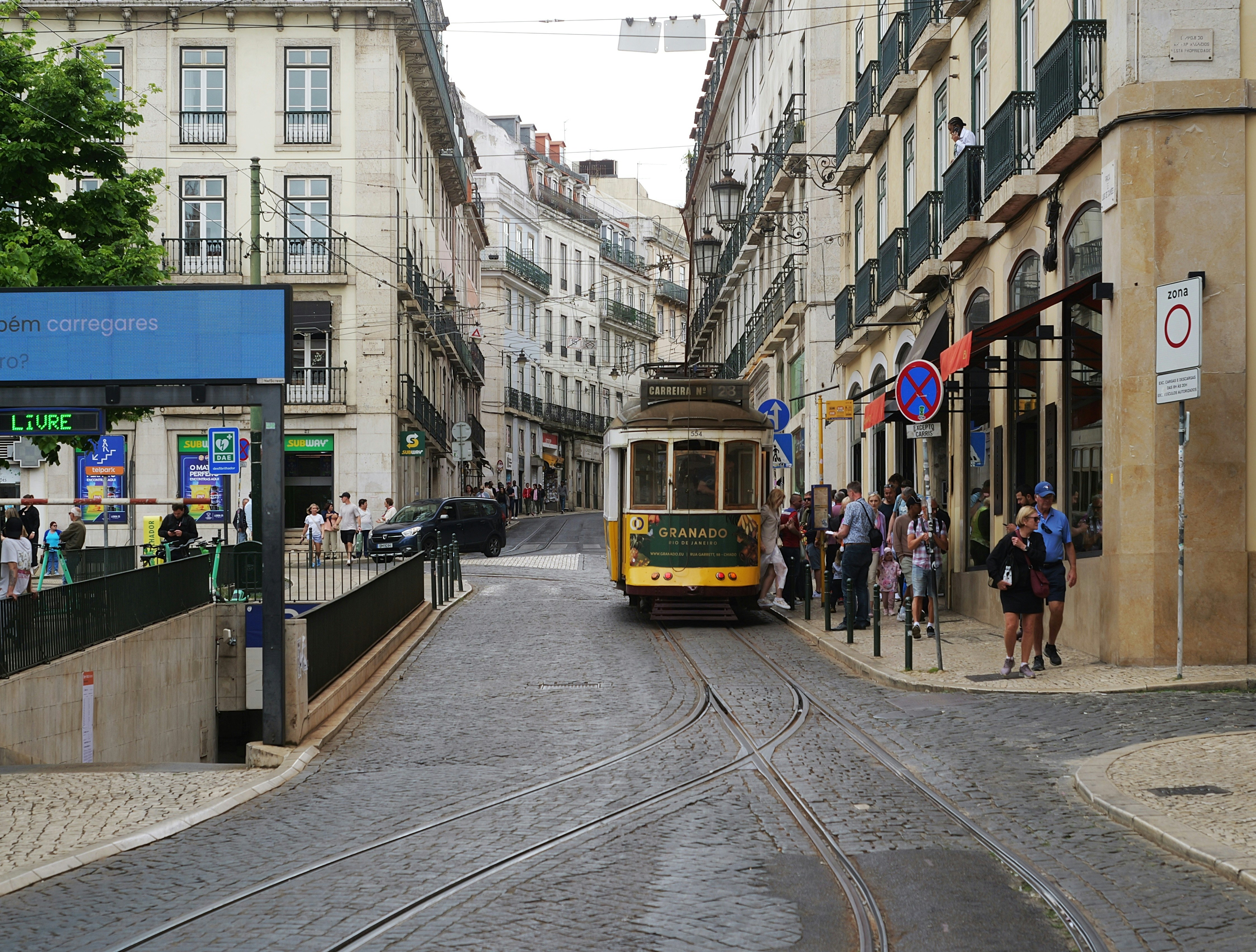Lisbon, city center, editorial | A yellow tram travels down a european city street.