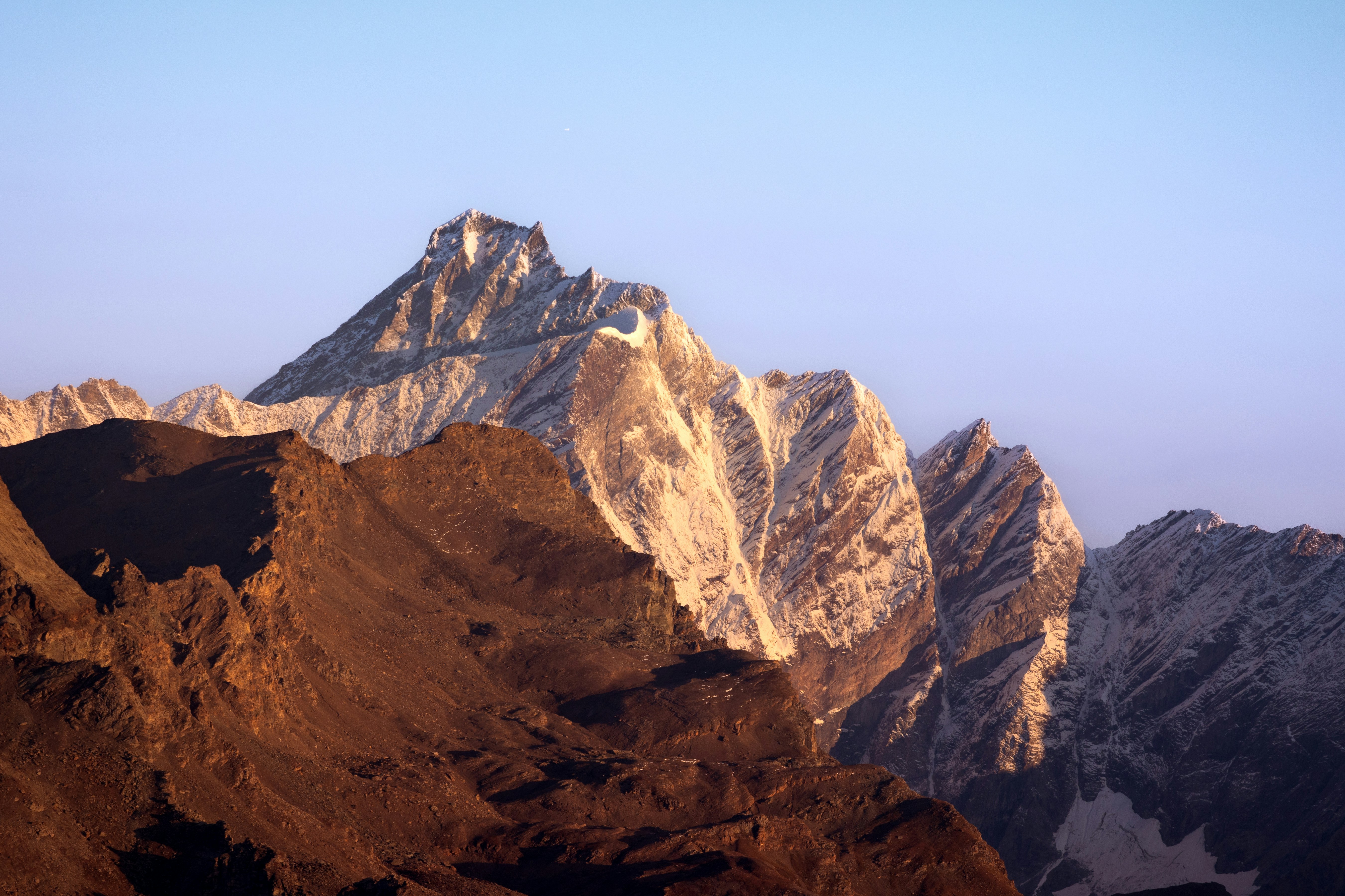 Majestic mountain range bathed in soft morning light, showcasing rugged terrain and snow-capped summits.