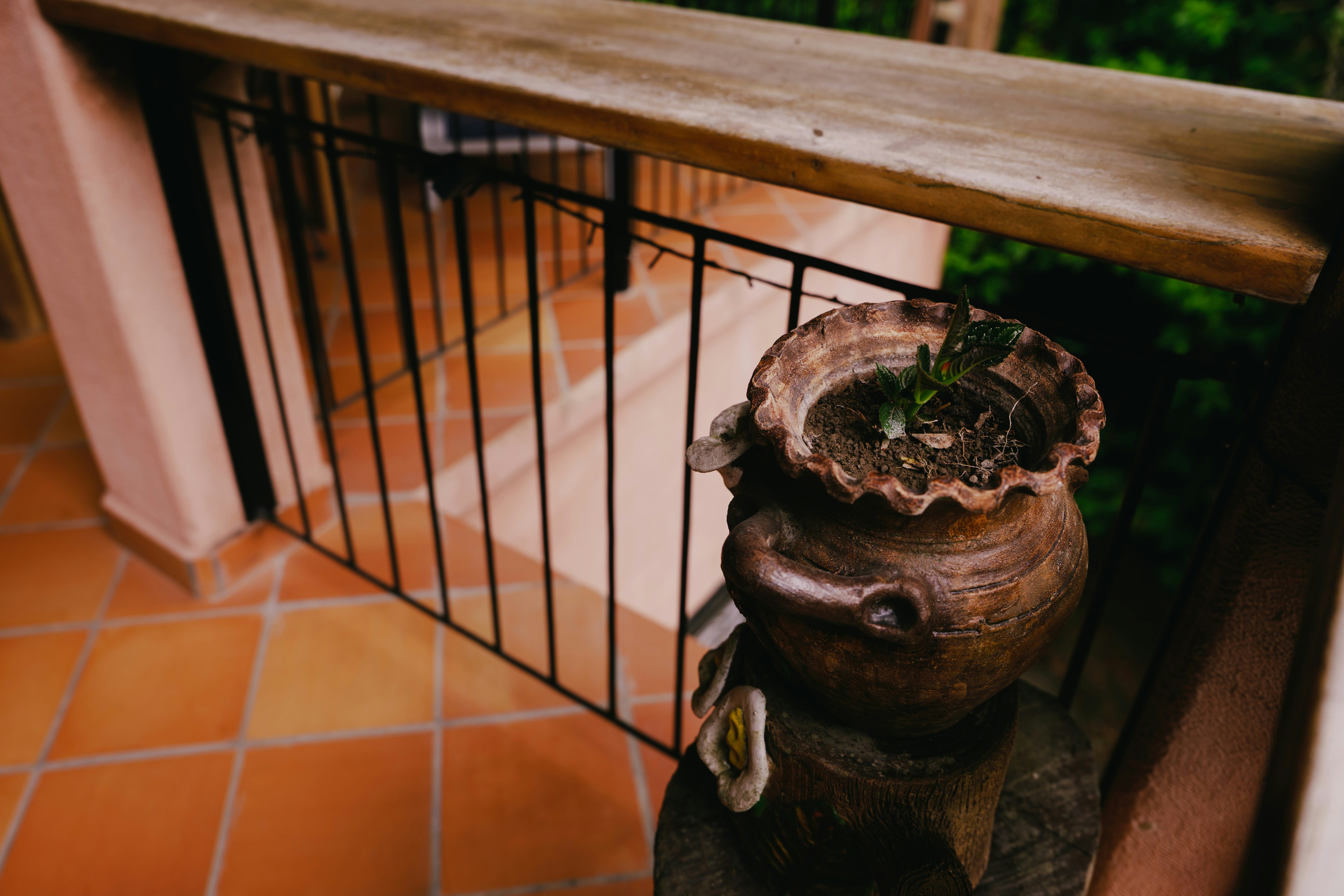 Weathered Terracotta Pot Framed by Balcony Rail in Warm Light
