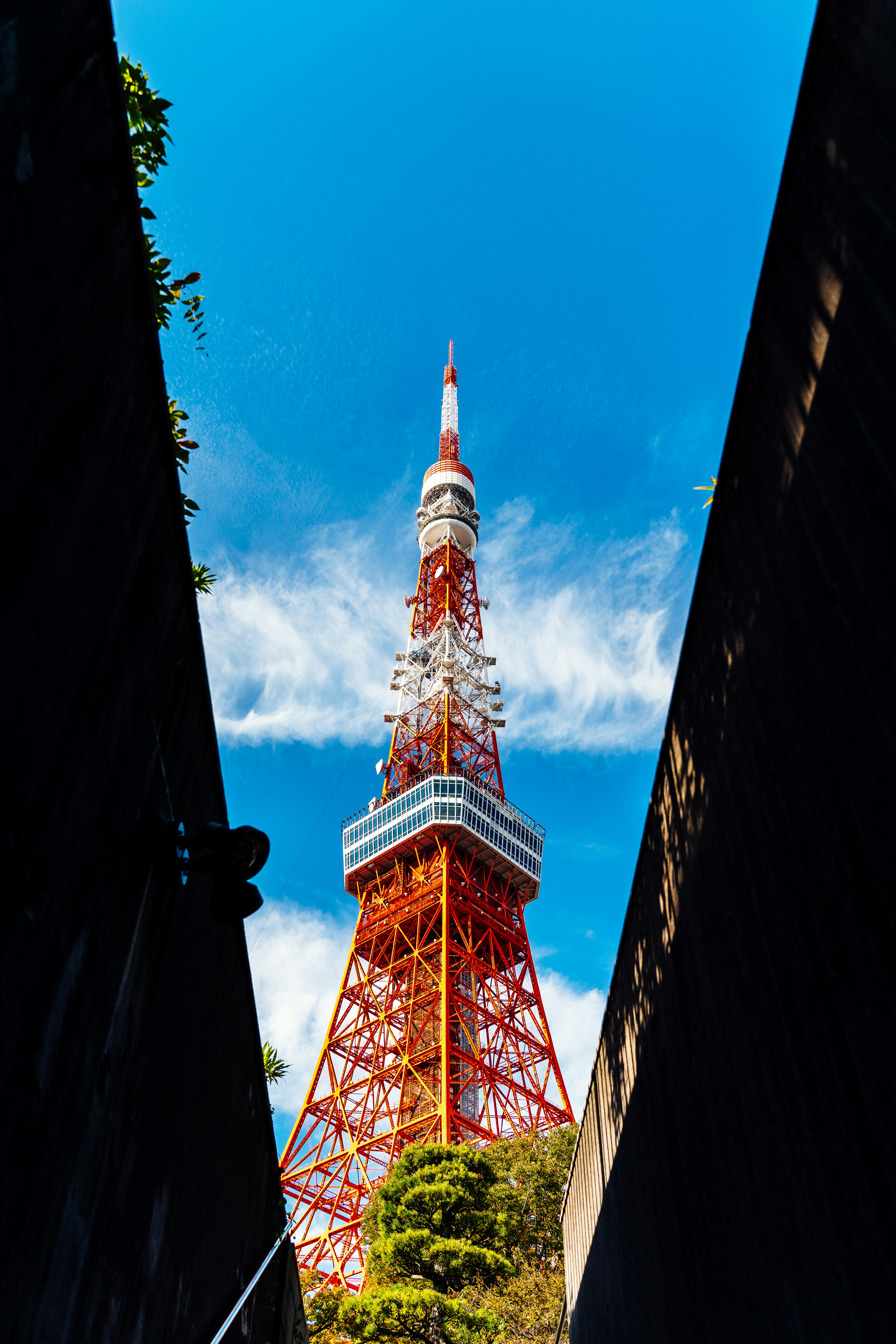 Tokyo tower is framed between buildings against a blue sky.