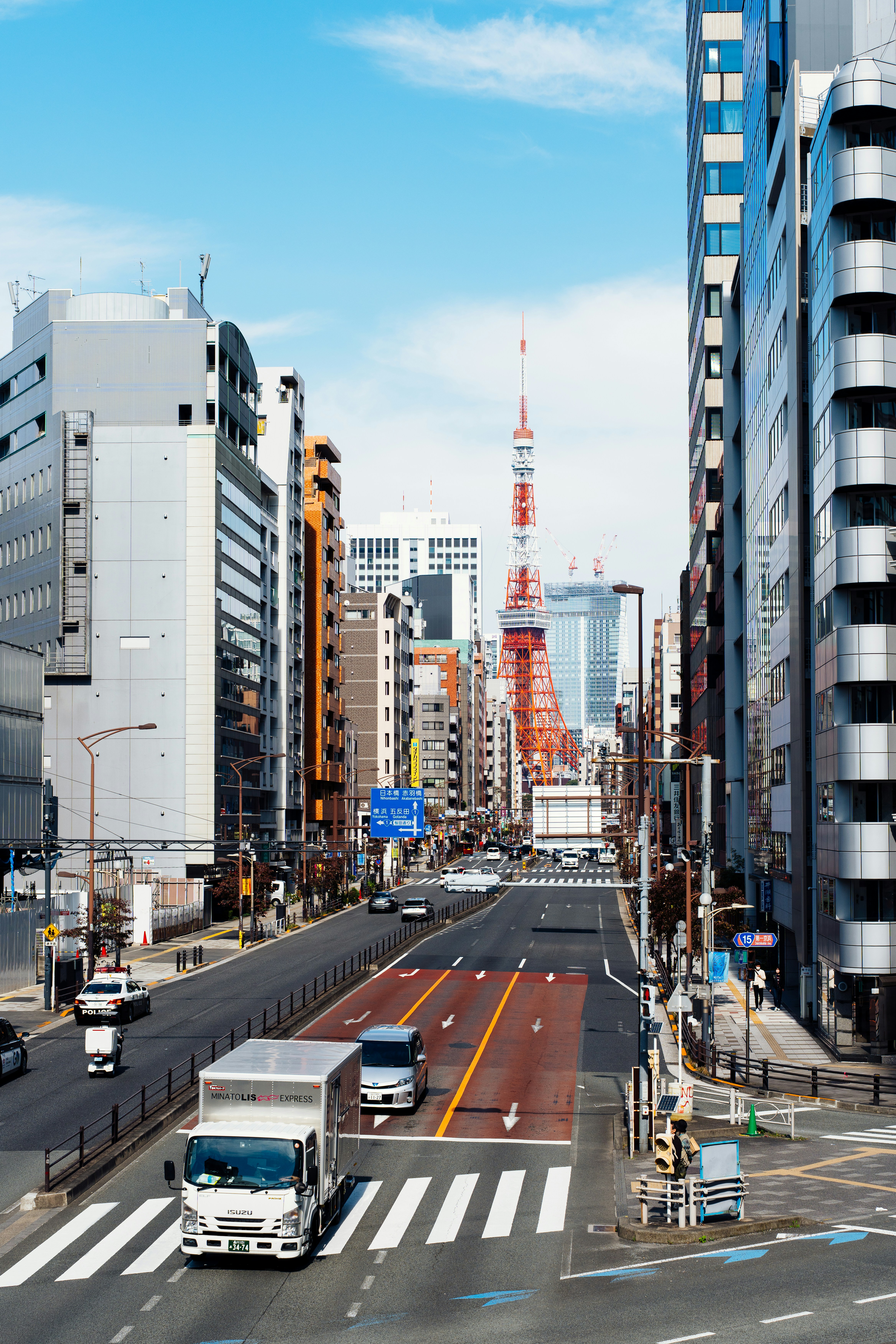 Vibrant cityscape featuring Tokyo Tower amidst modern skyscrapers, with bustling traffic on the road below.