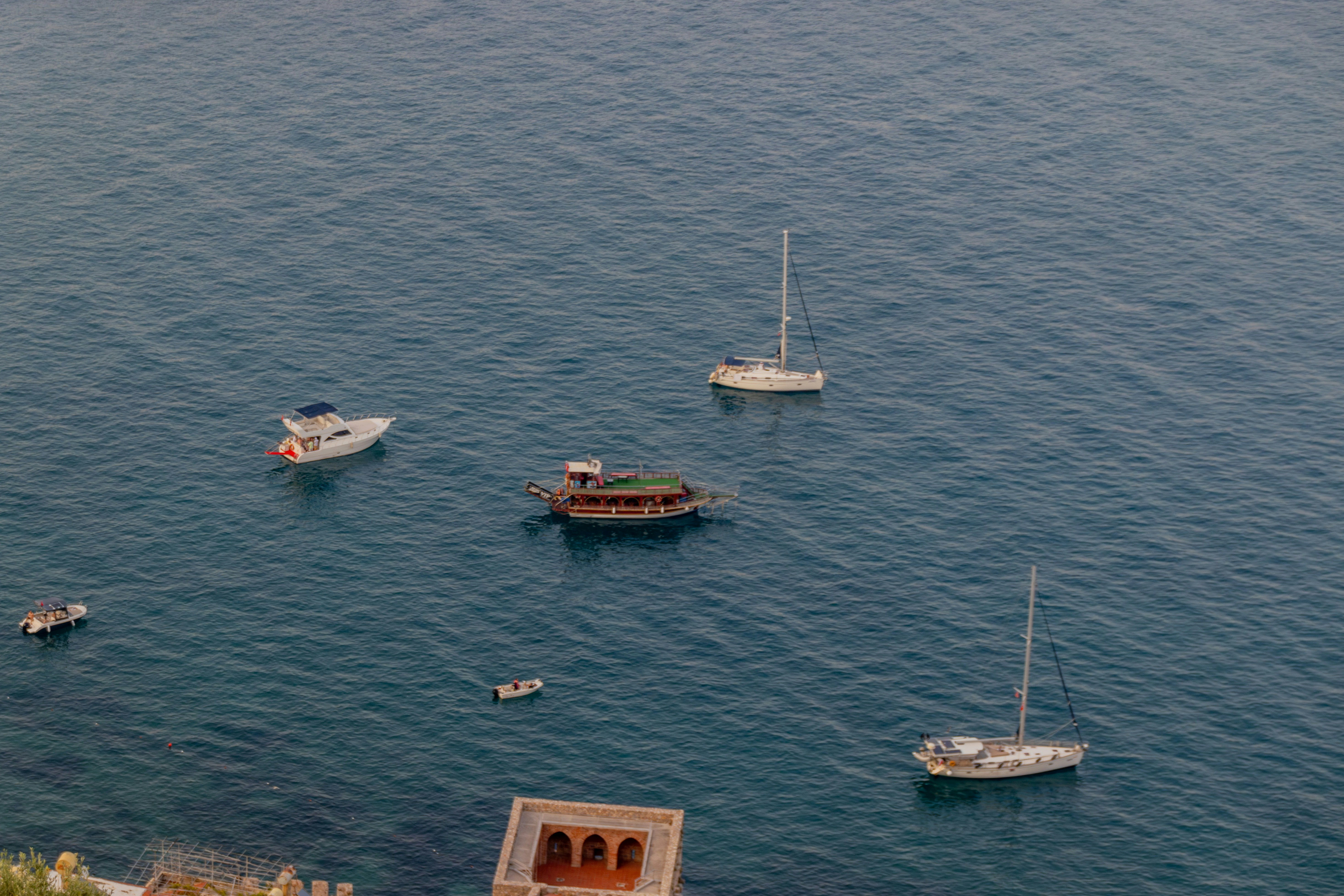 Alanya port | Boats are floating on the blue ocean water.