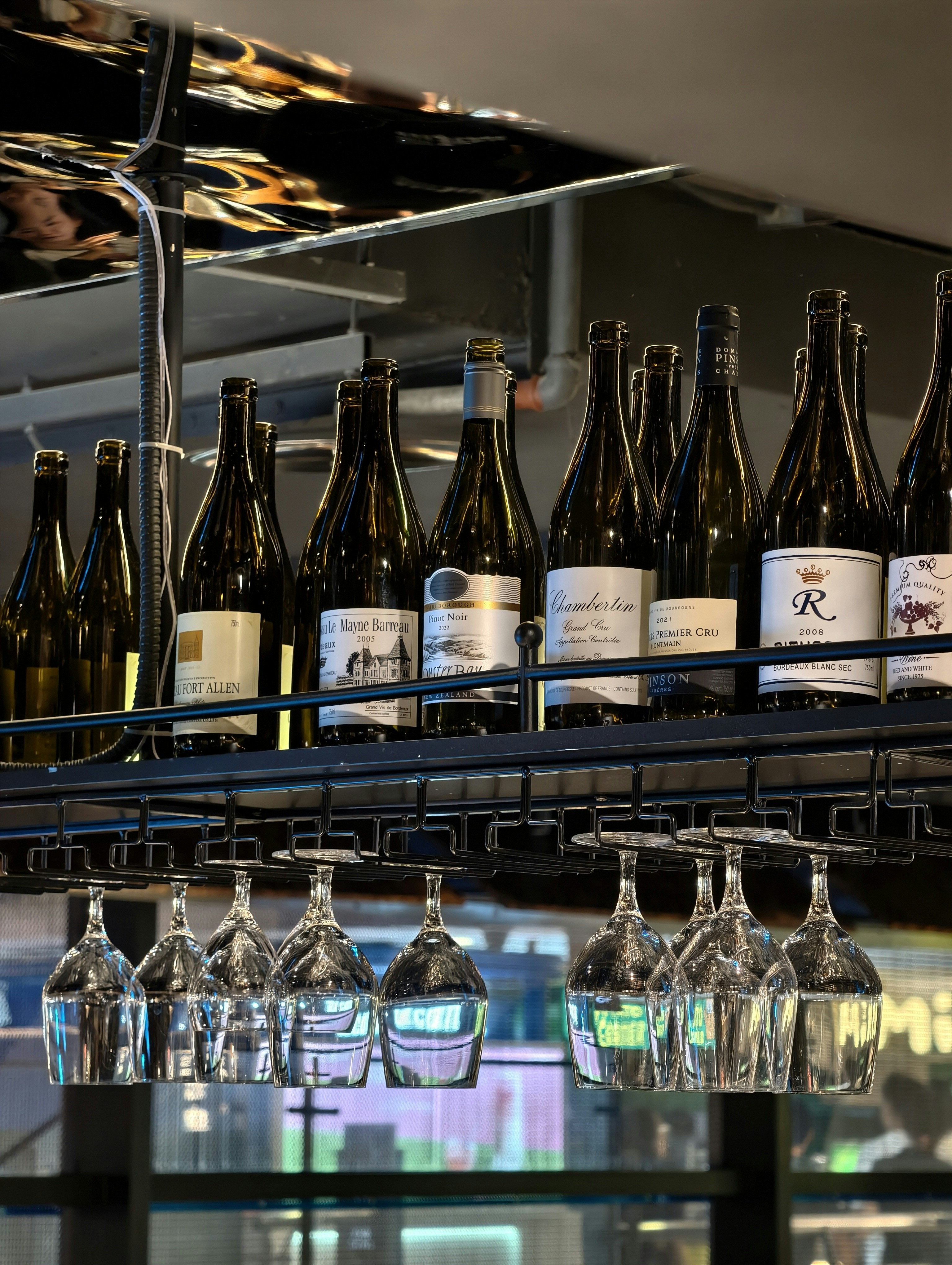 Wine bottles and glasses are displayed in a bar.