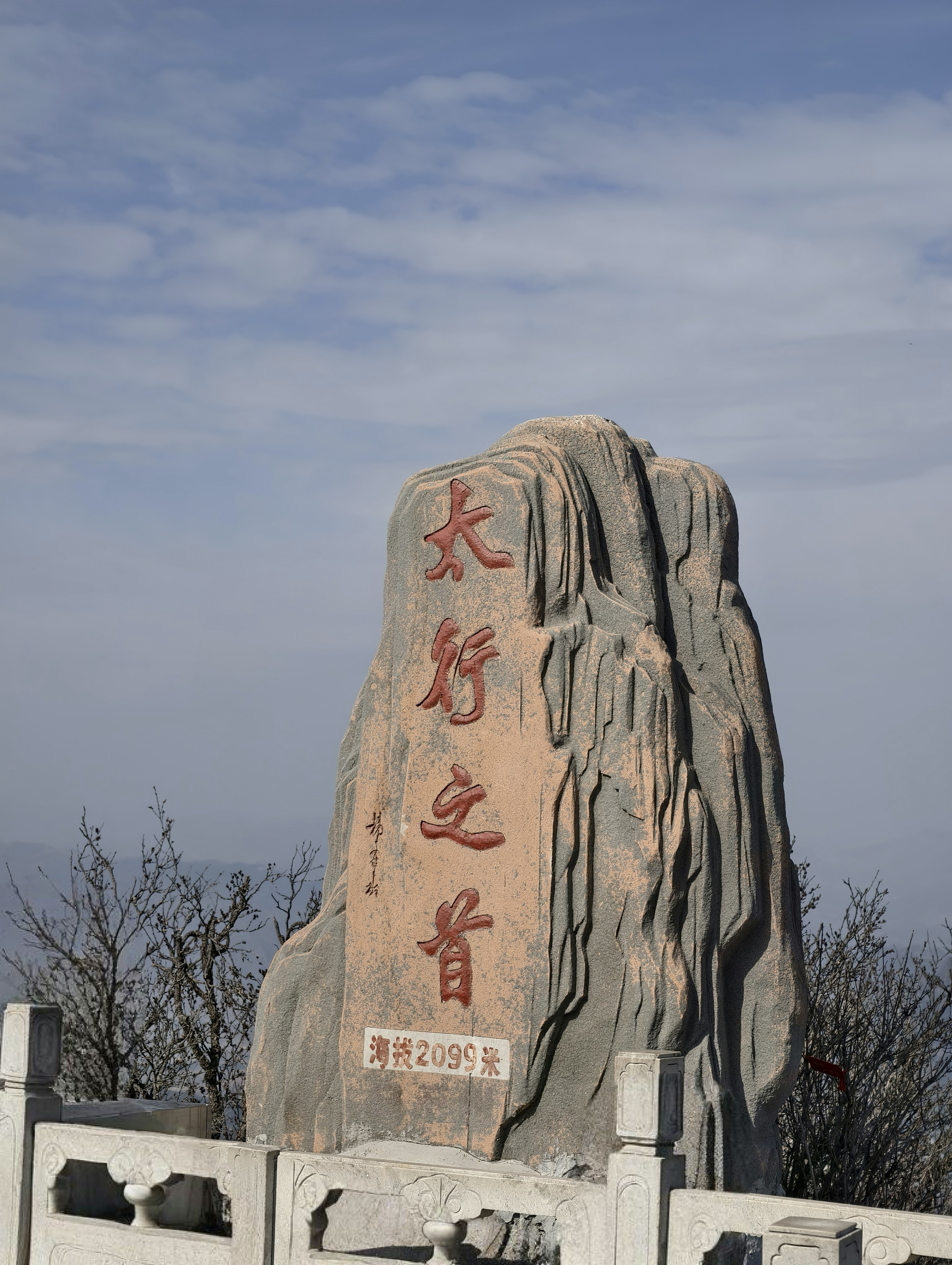 Large rock with chinese characters in a scenic area.