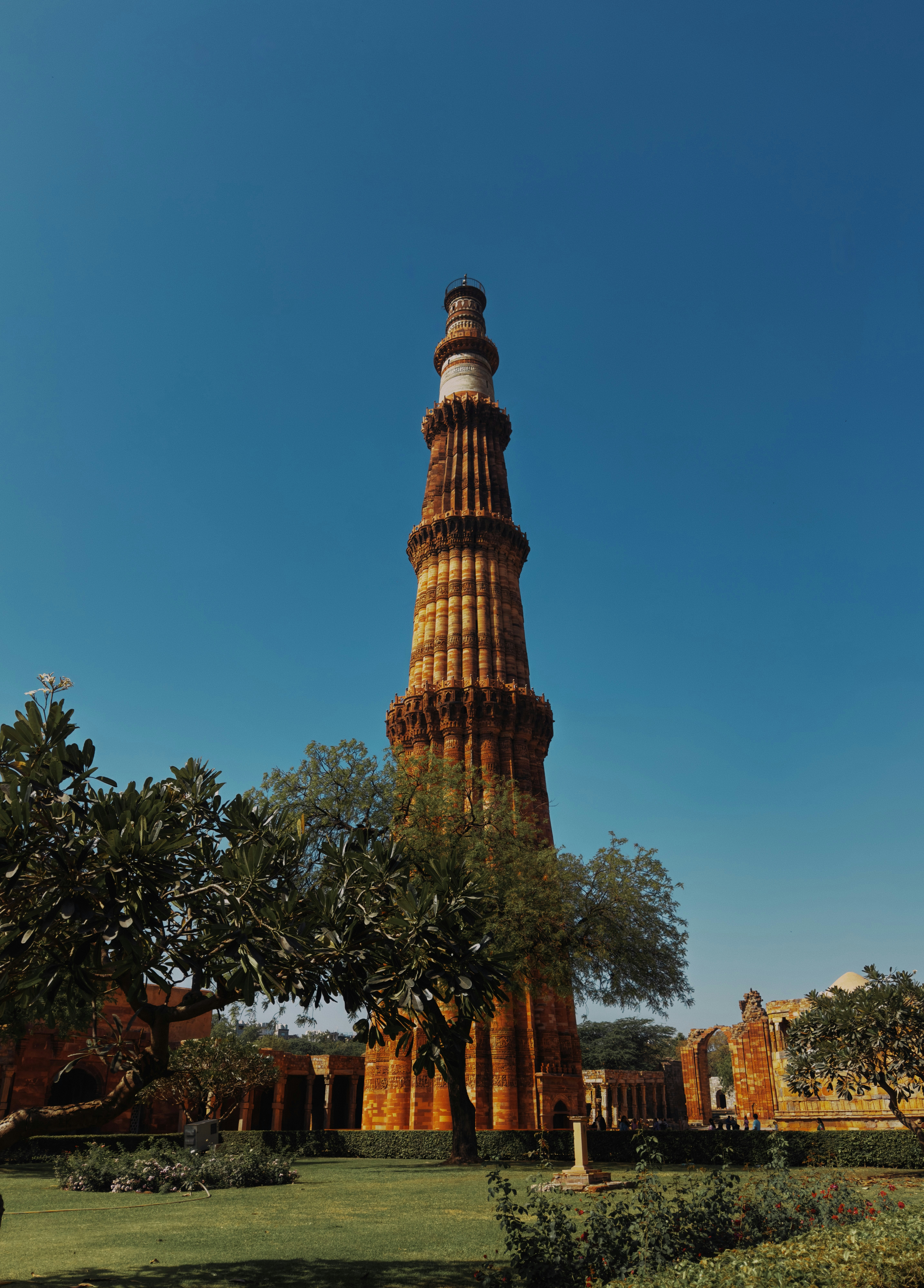 Qutab Minar | The qutub minar stands tall against a blue sky.