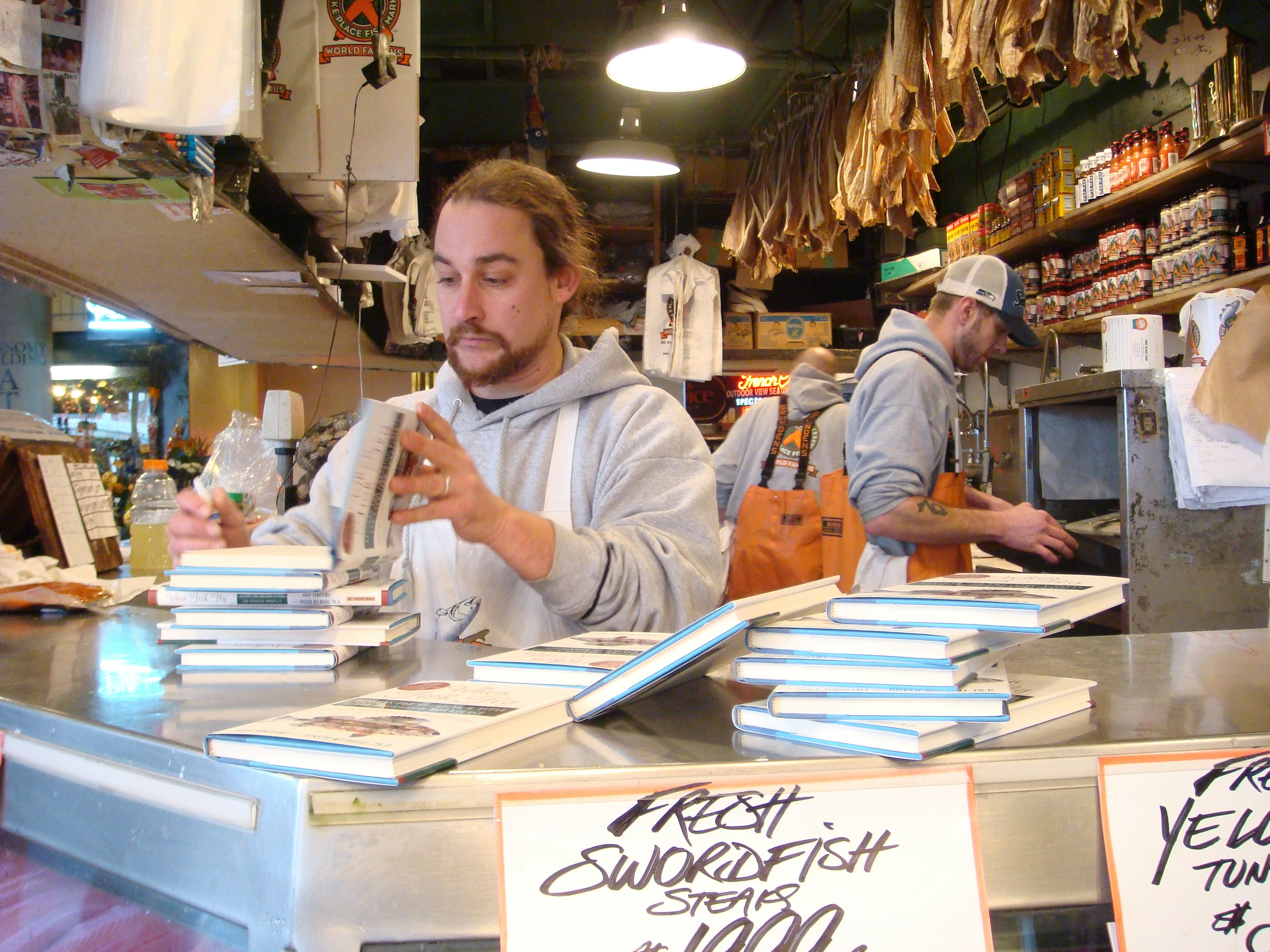 Two men organize books at a counter.