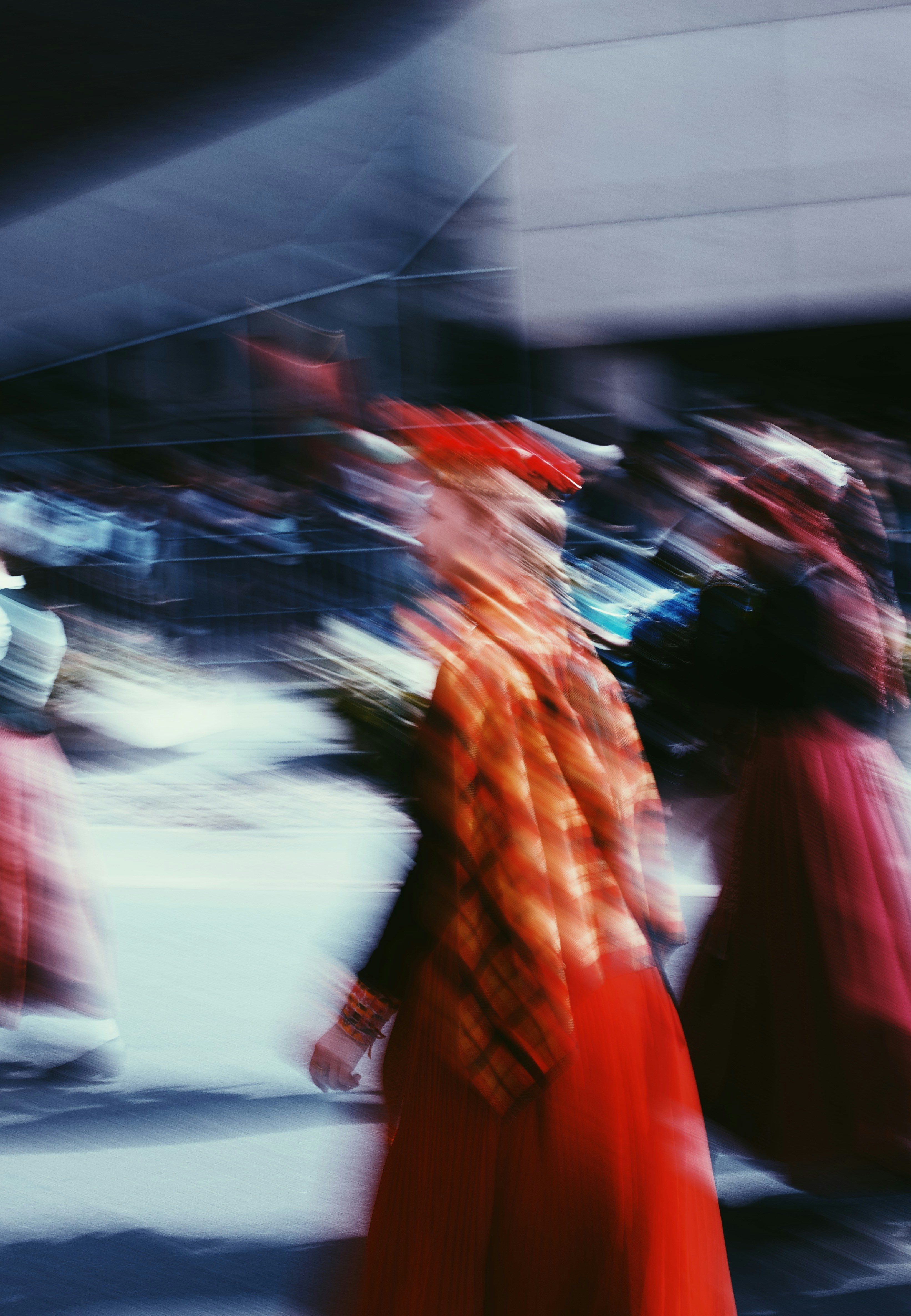 Red-robe silhouettes in motion blur at a modern architectural plaza