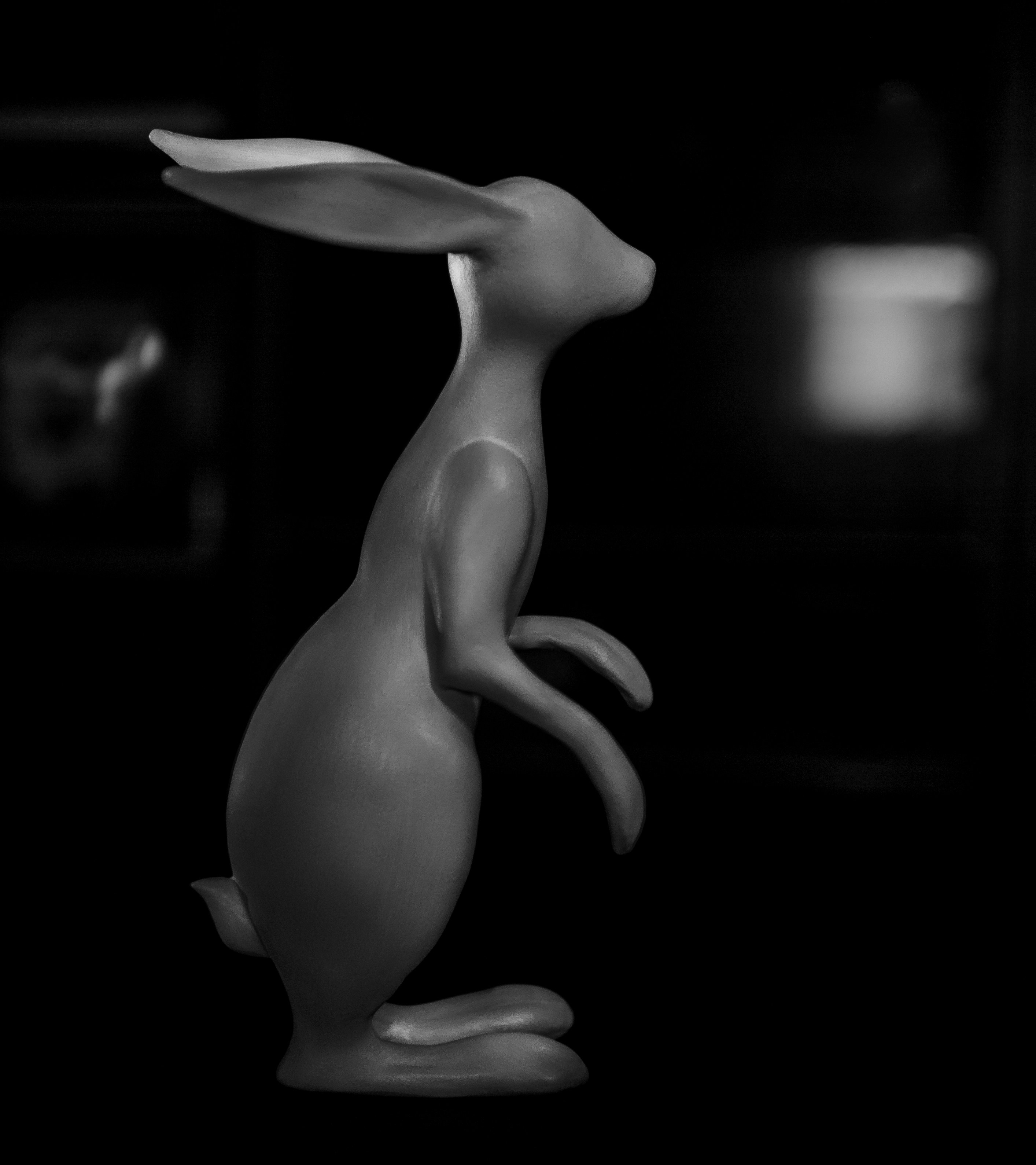 Stylized rabbit sculpture in monochrome, highlighting its graceful posture against a dark background.