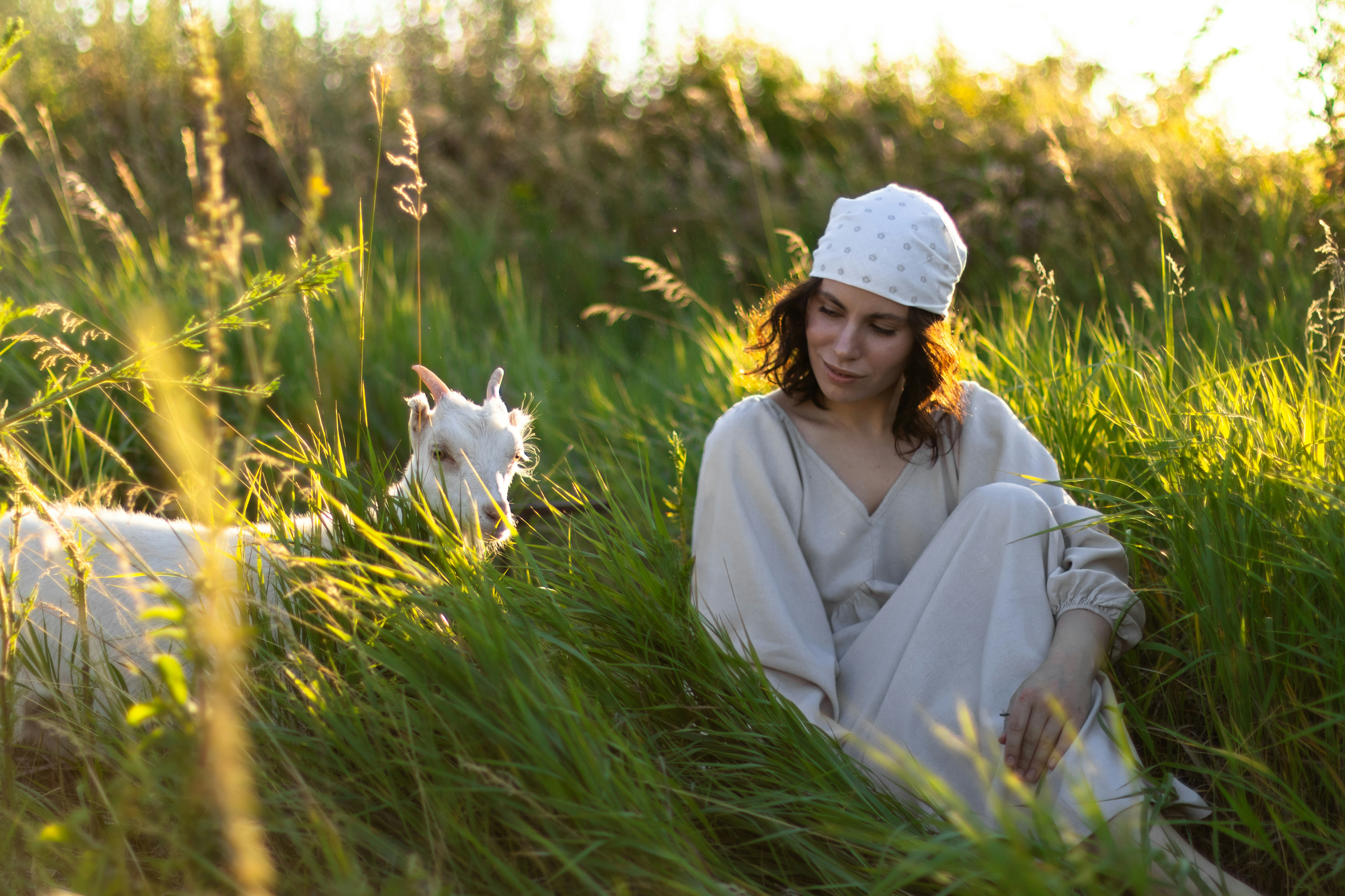 A woman and a goat relax in tall grass. photo – Free Woman Image on ...