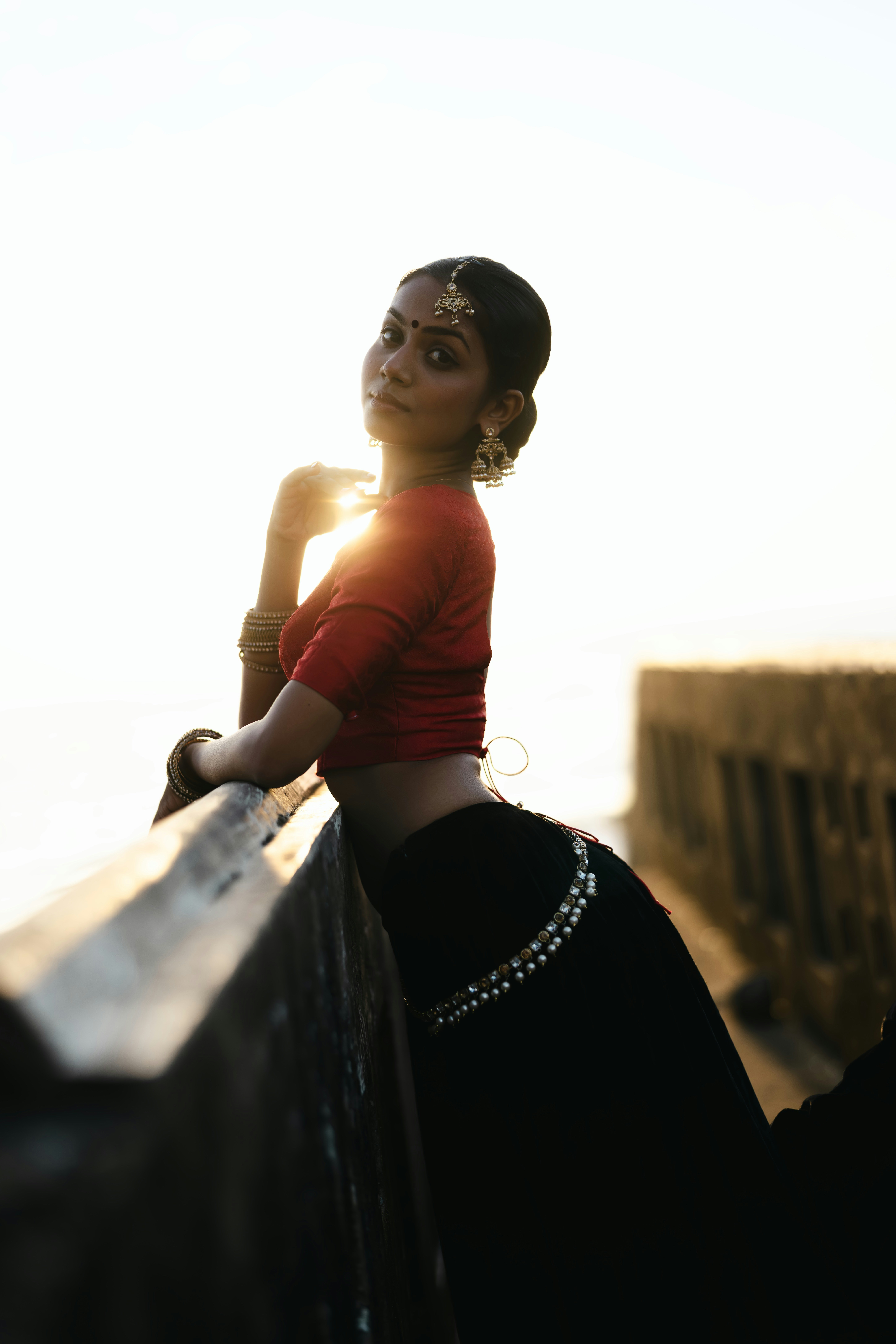 A woman in traditional South Indian attire poses gracefully on the beach during golden hour at Mount Lavinia, Sri Lanka. This portrait captures a fusion of classical Indian dance-inspired expression and the coastal serenity of Sri Lanka. Photographed using a Sony A7RV and a 50mm f/1.2 GM lens. | Woman poses gracefully in cultural attire.
