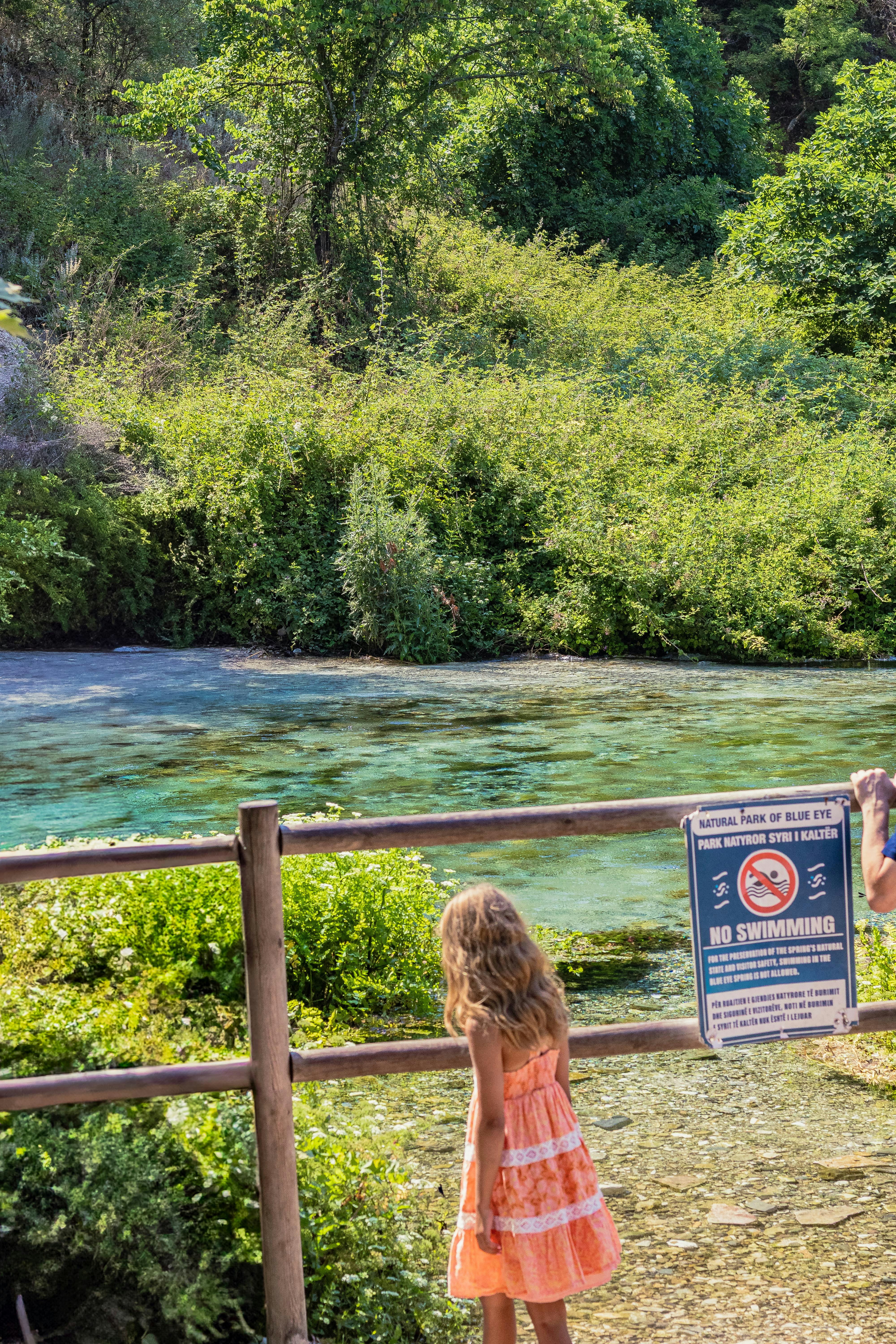 Girl looks at a clear blue river.