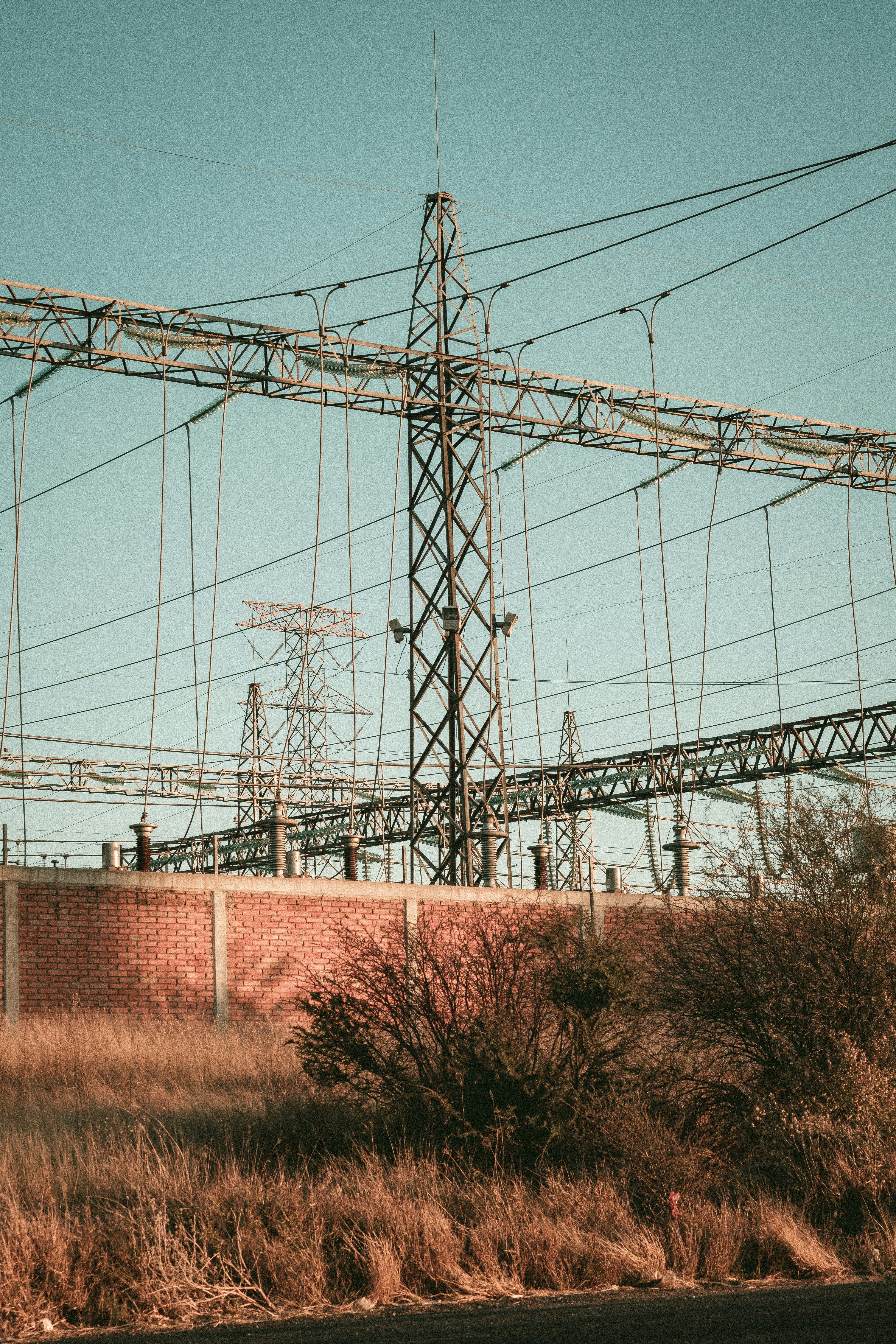 Power lines tower against a clear blue sky.