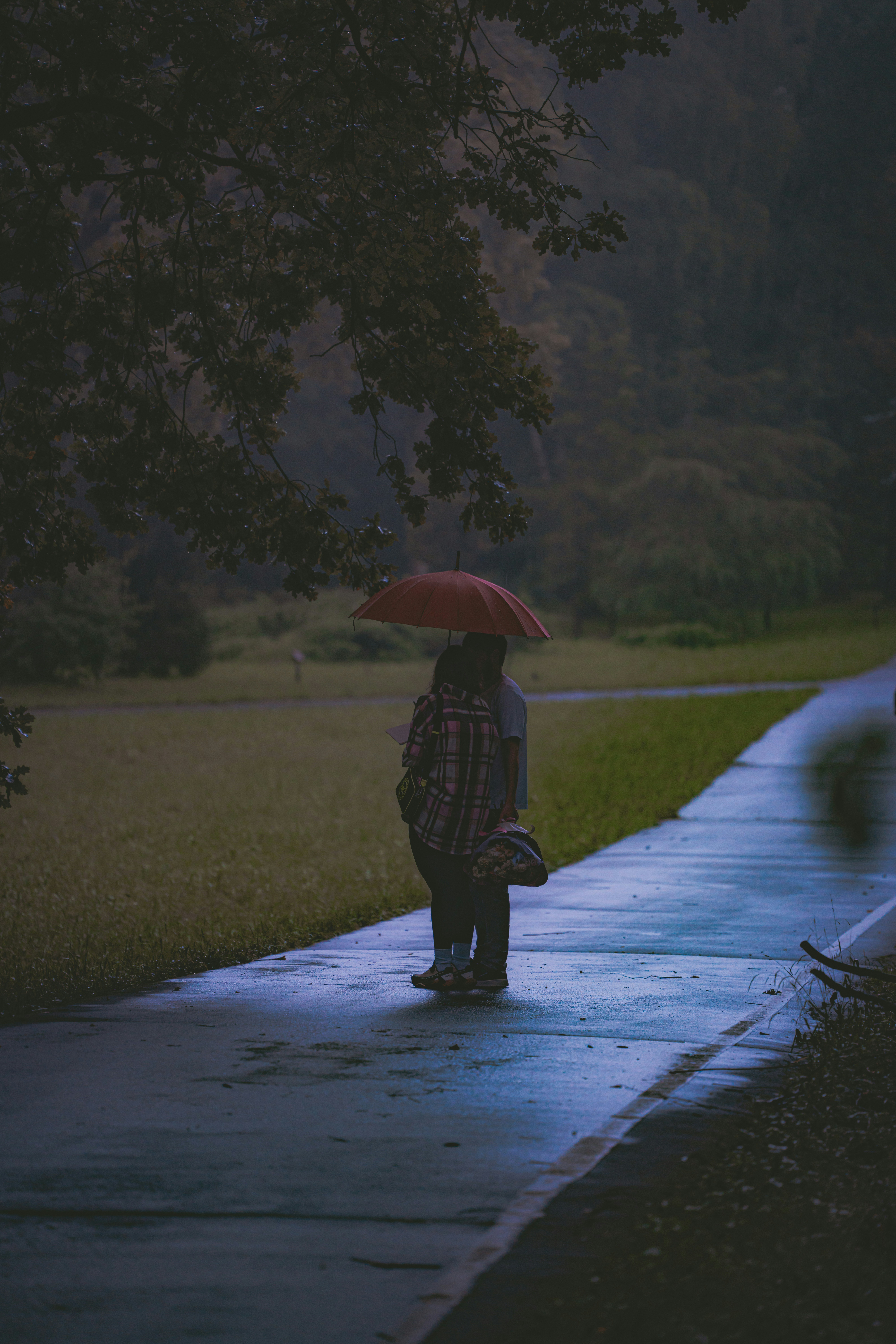 A person stands alone under an umbrella in the rain.
