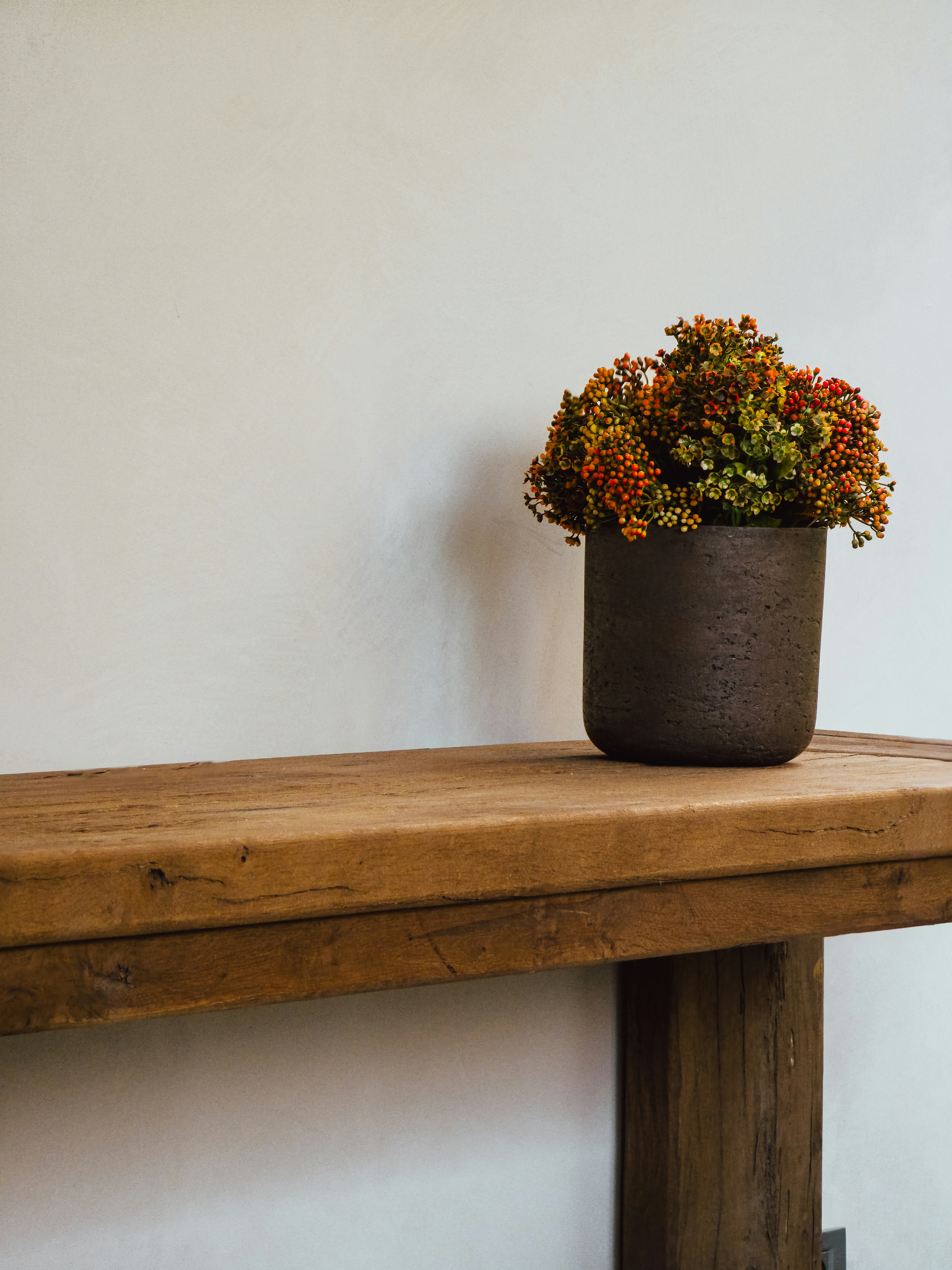 Flowers in a vase rest on a wooden bench.