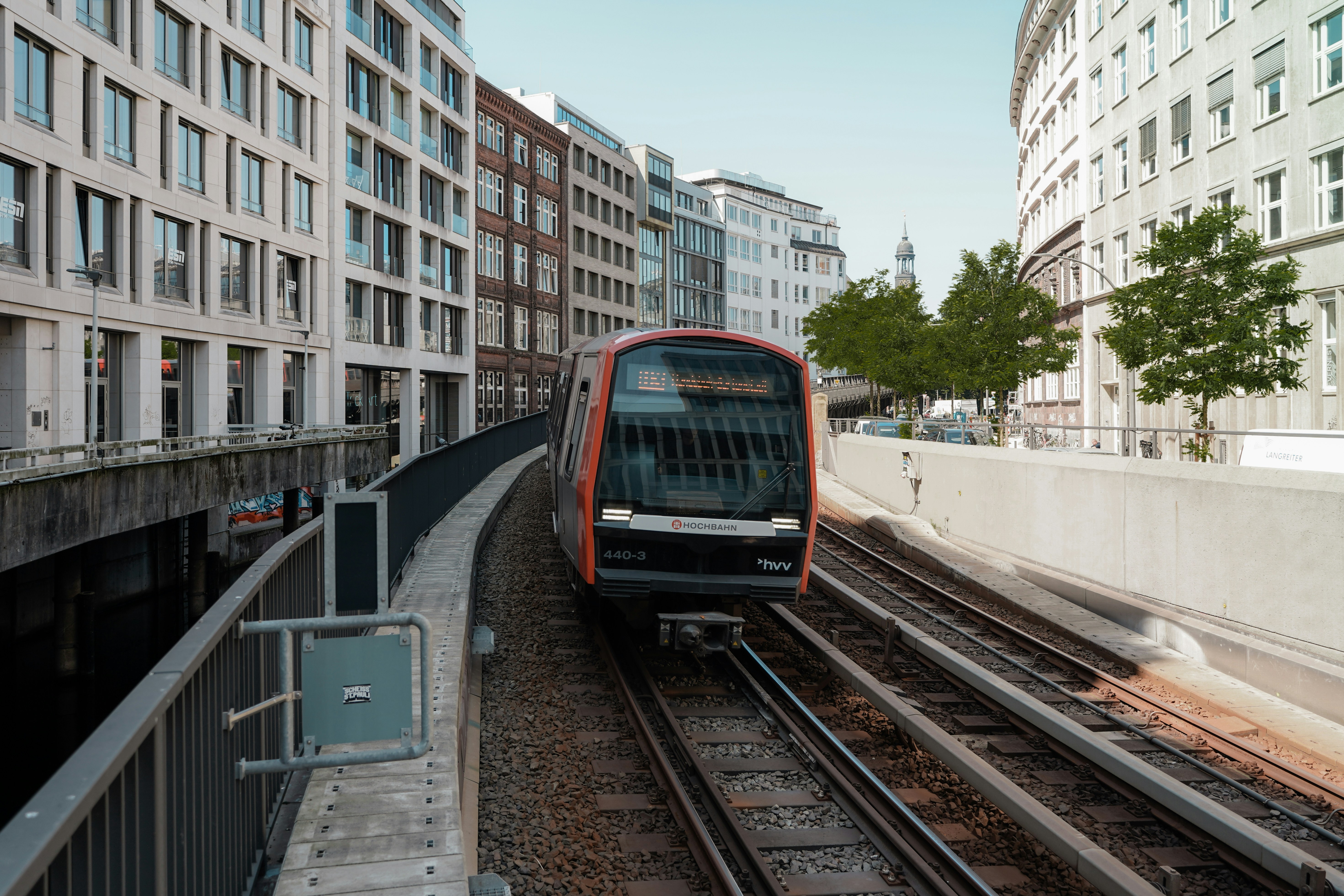 Train travels through a city next to buildings.