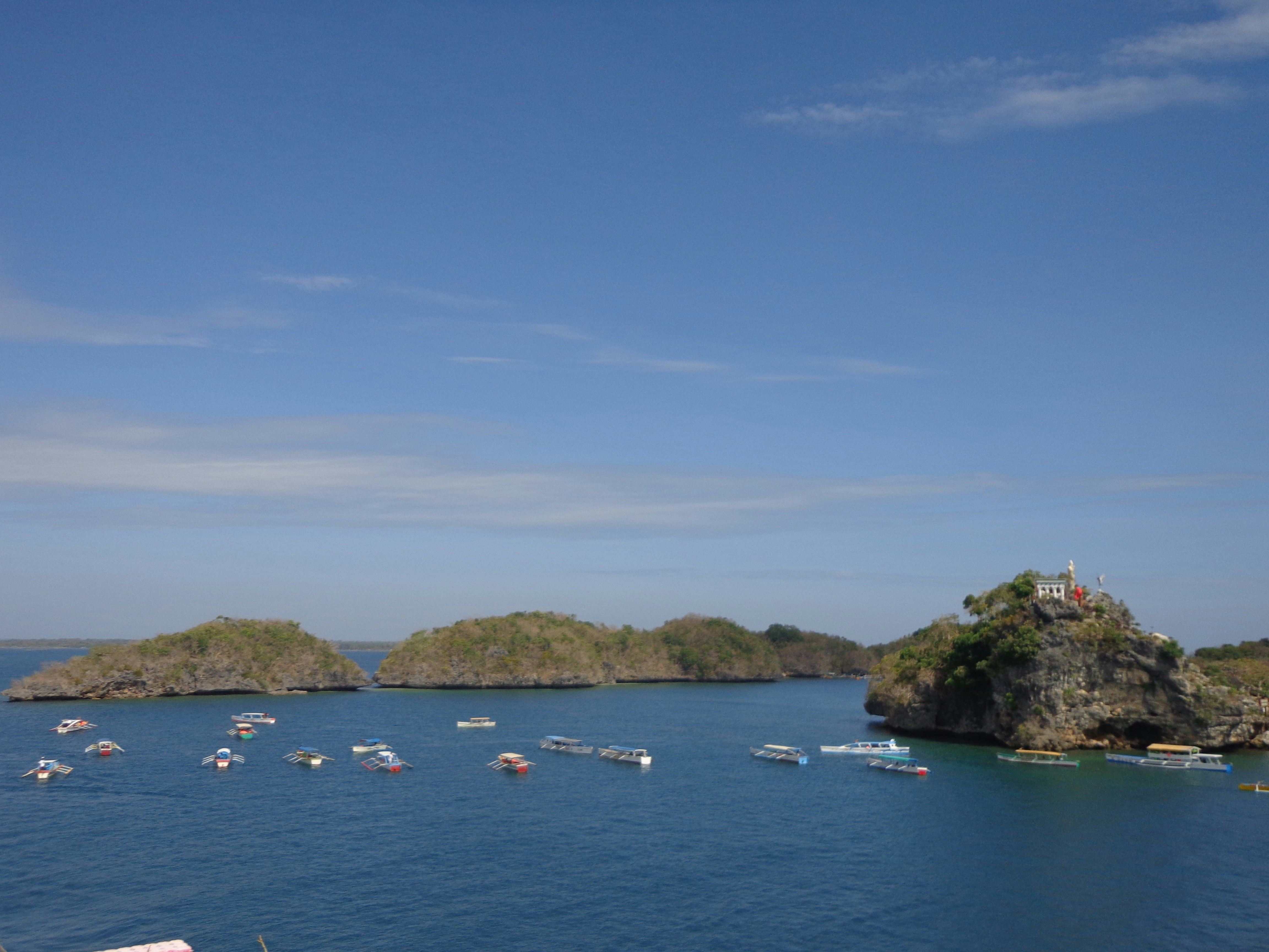 Serene coastal landscape featuring lush islands and anchored boats in clear blue waters under a bright sky.