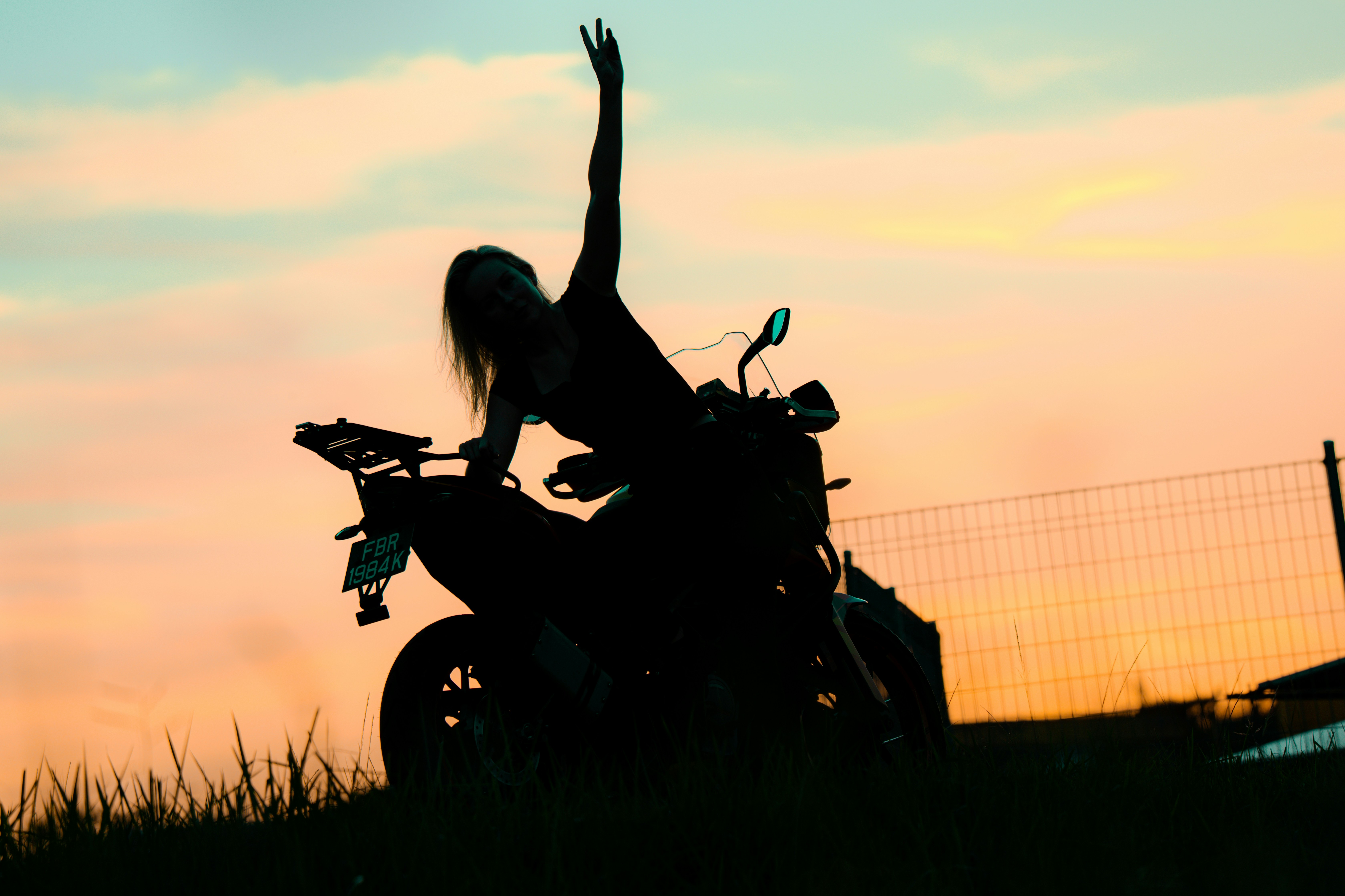 Silhouetted figure on a motorcycle against a vibrant sunset, embodying the spirit of adventure and freedom.