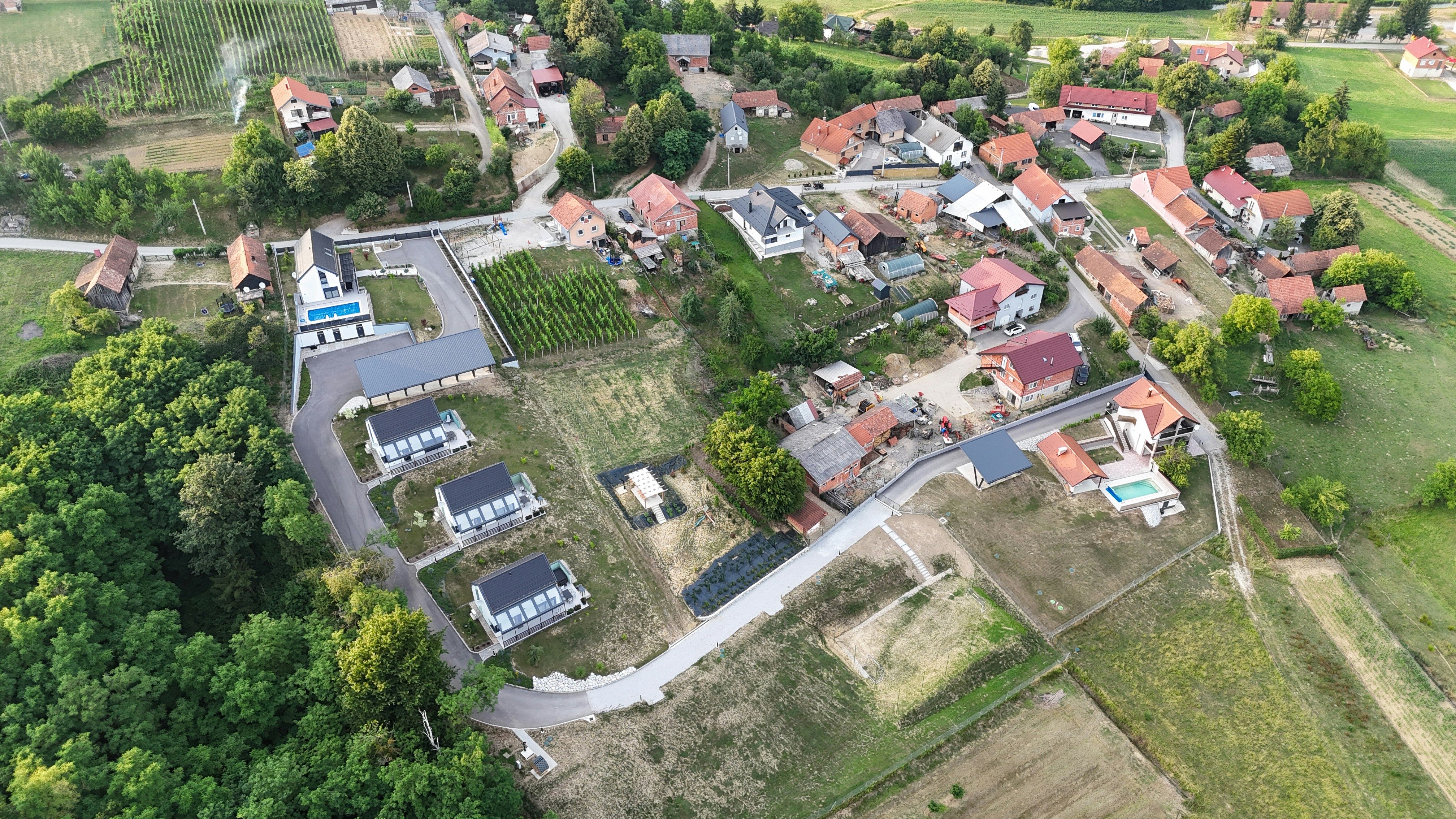Aerial view of a quaint village surrounded by lush greenery and agricultural fields, showcasing the harmony of nature and community life.