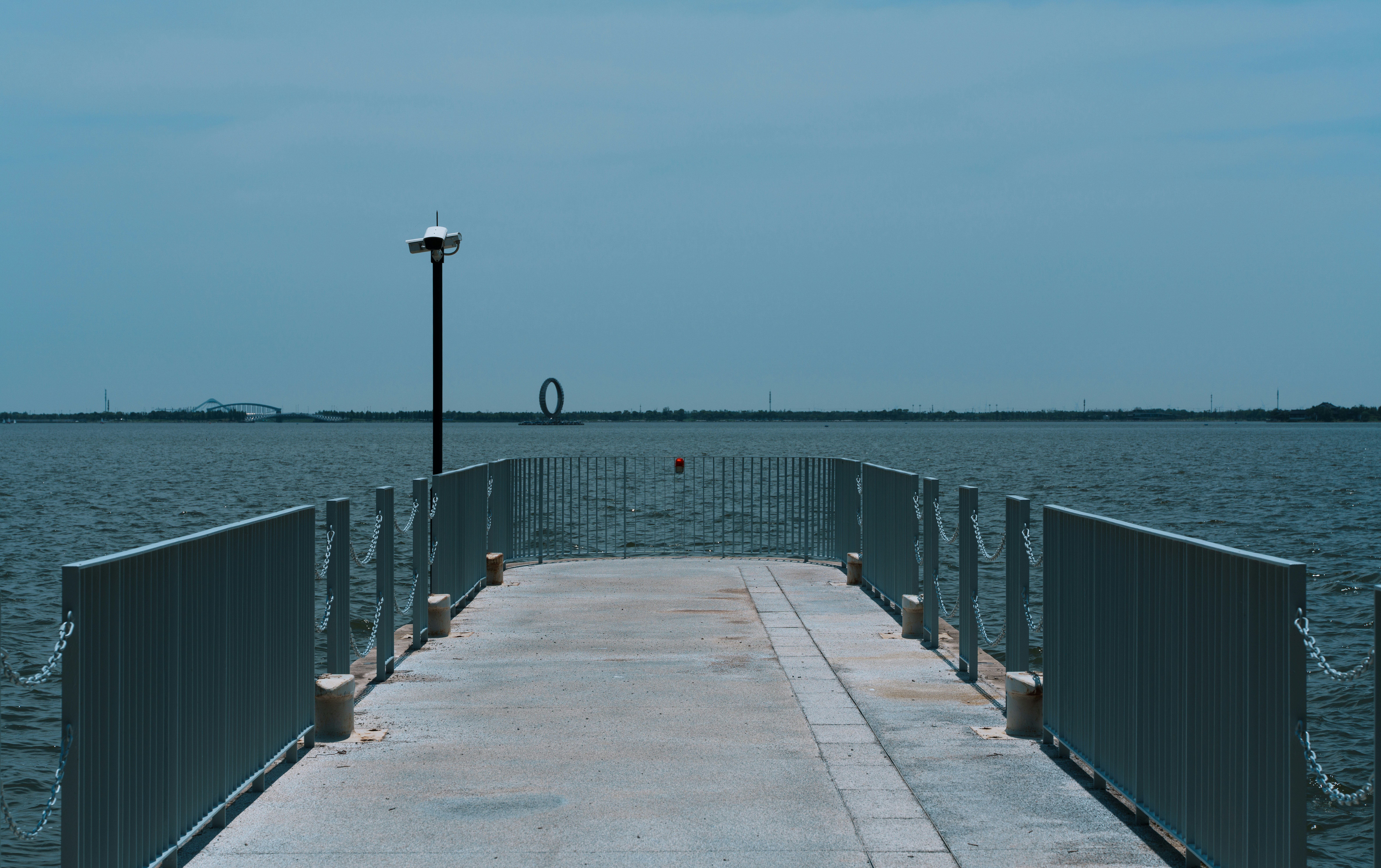 A pier extends into calm water under a blue sky.